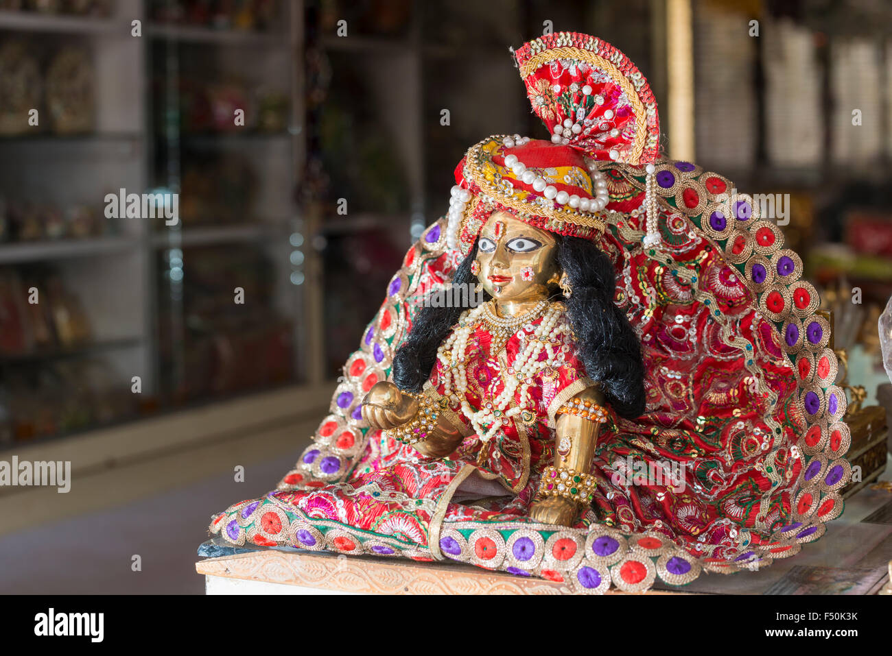 A little figure of the god Krishna, dressed in colorful material and ...