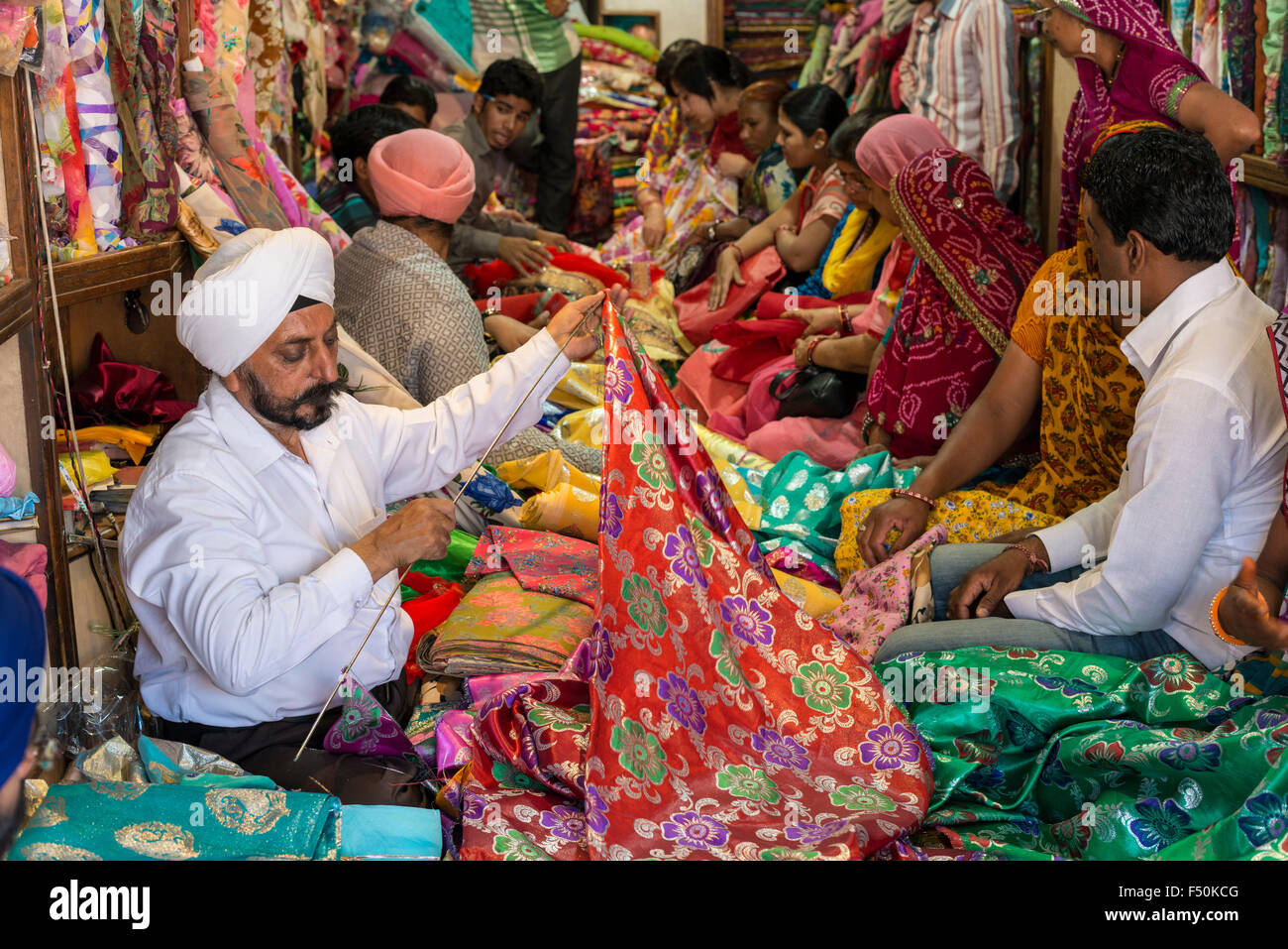 A salesman is promoting colorful material in his shop in a small street ...