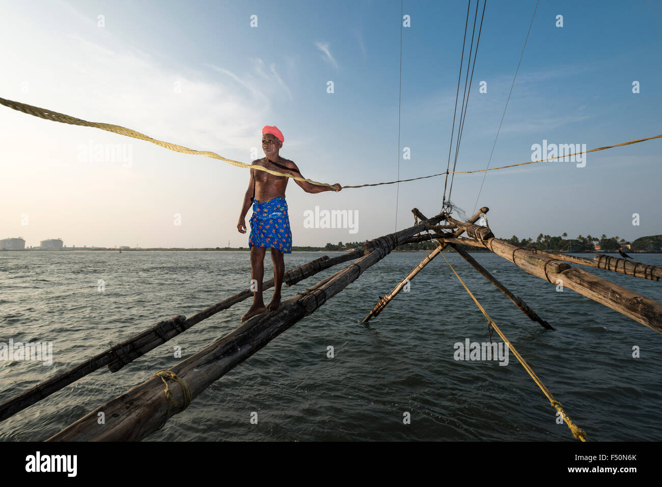 One man is are walking on the net pole of a chinese fishing net to get ...