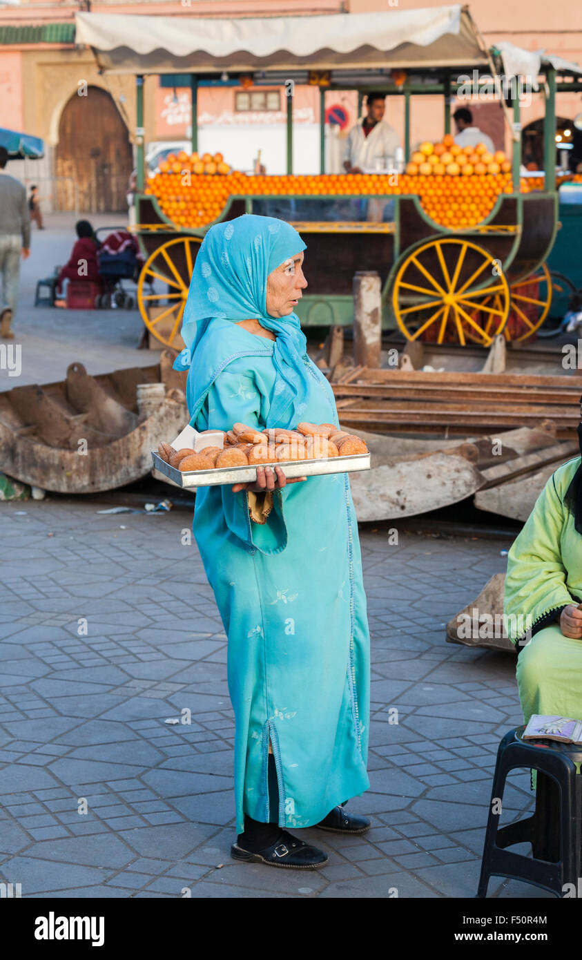 Local Muslim woman in blue jilbab holding a tray of cakes, Jamaa el Fna ...