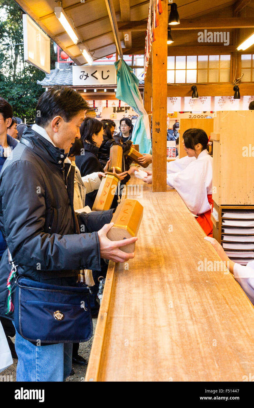 Japan, Nishinomiya shrine, New year Day, Shogatsu. Man buying omikuji ...