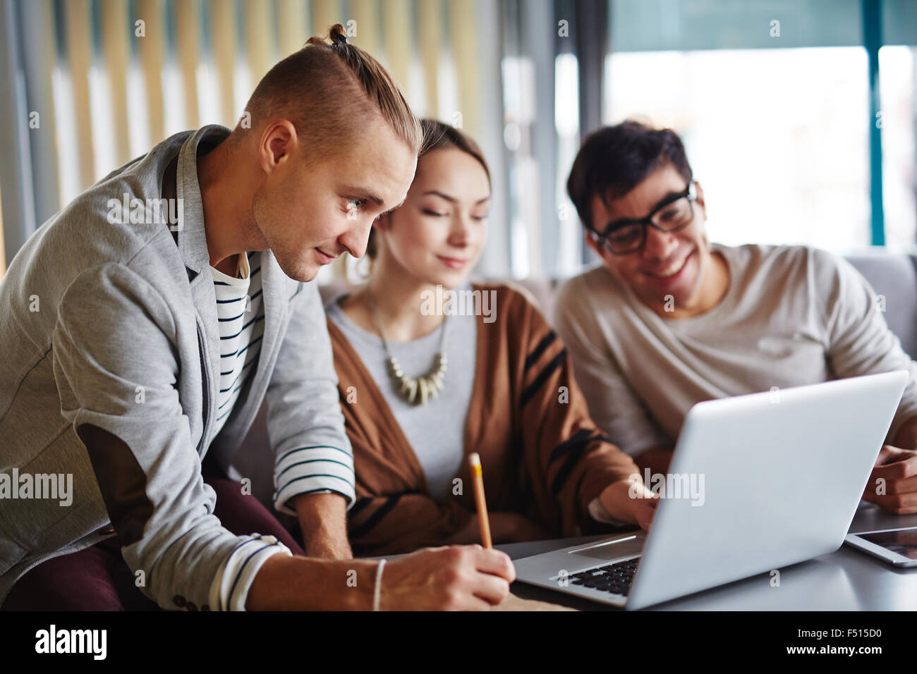 Young friends or colleagues looking at laptop screen Stock Photo - Alamy