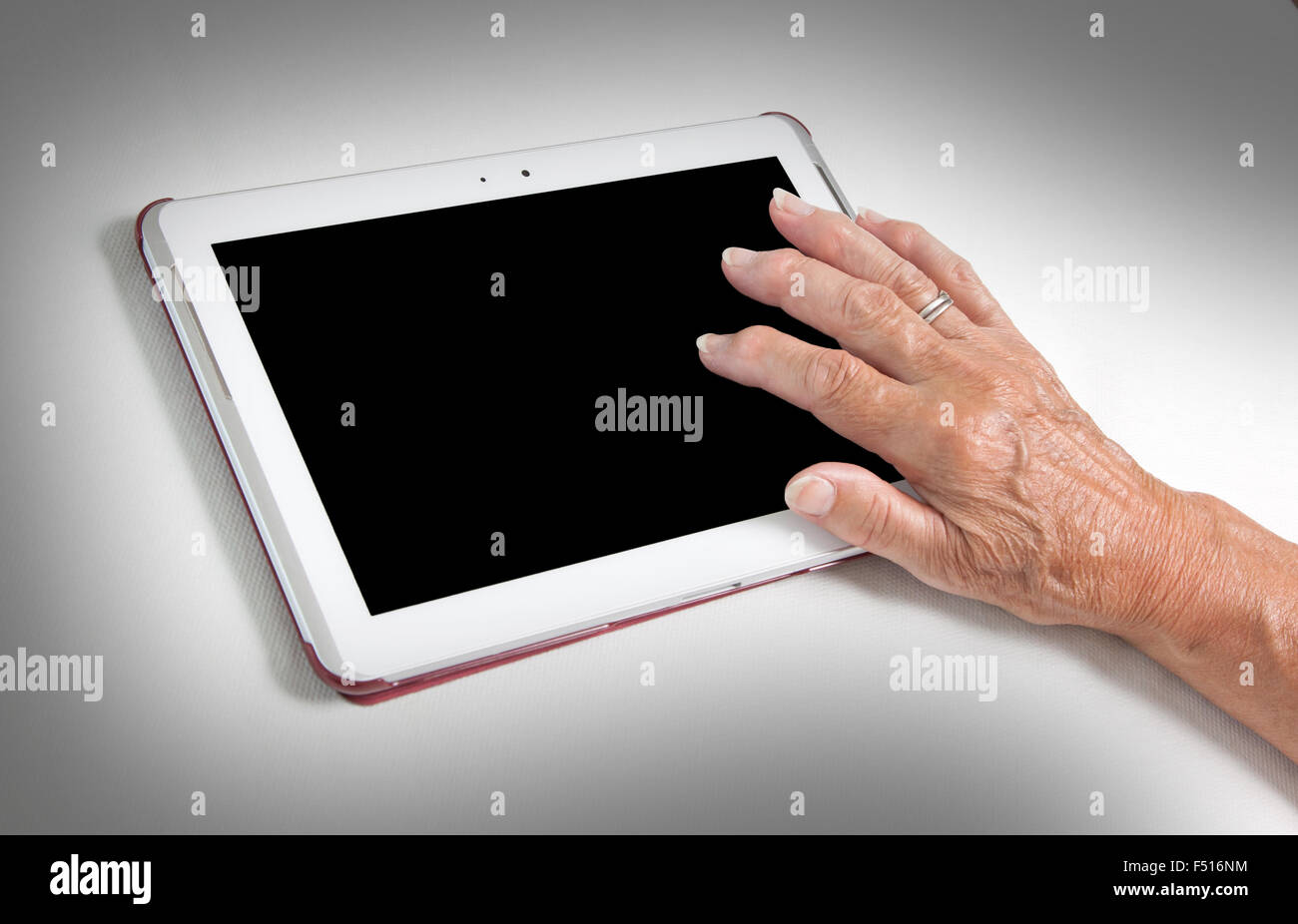 Hand of senior lady relaxing and reading the screen of her tablet ...