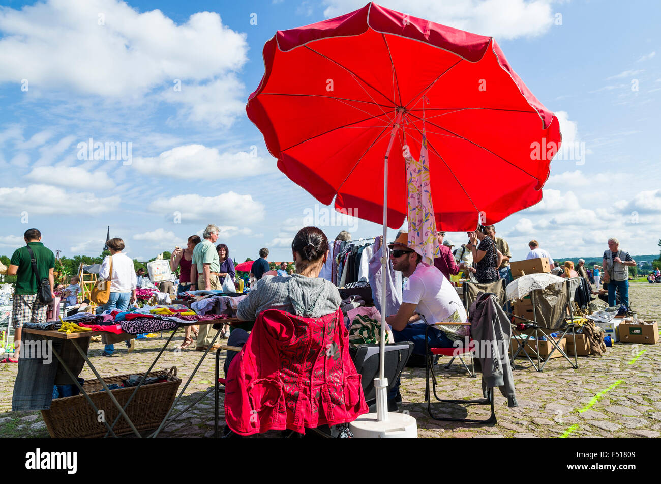 Merchants sitting under a red umbrella in between their goods at the ...