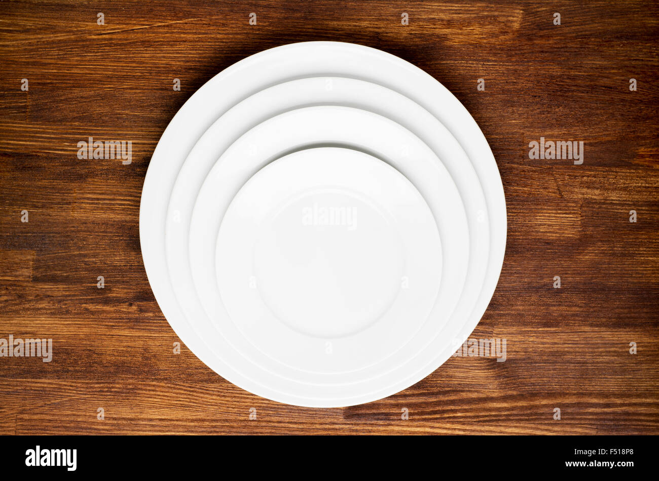 Empty white plates on wooden table Stock Photo - Alamy