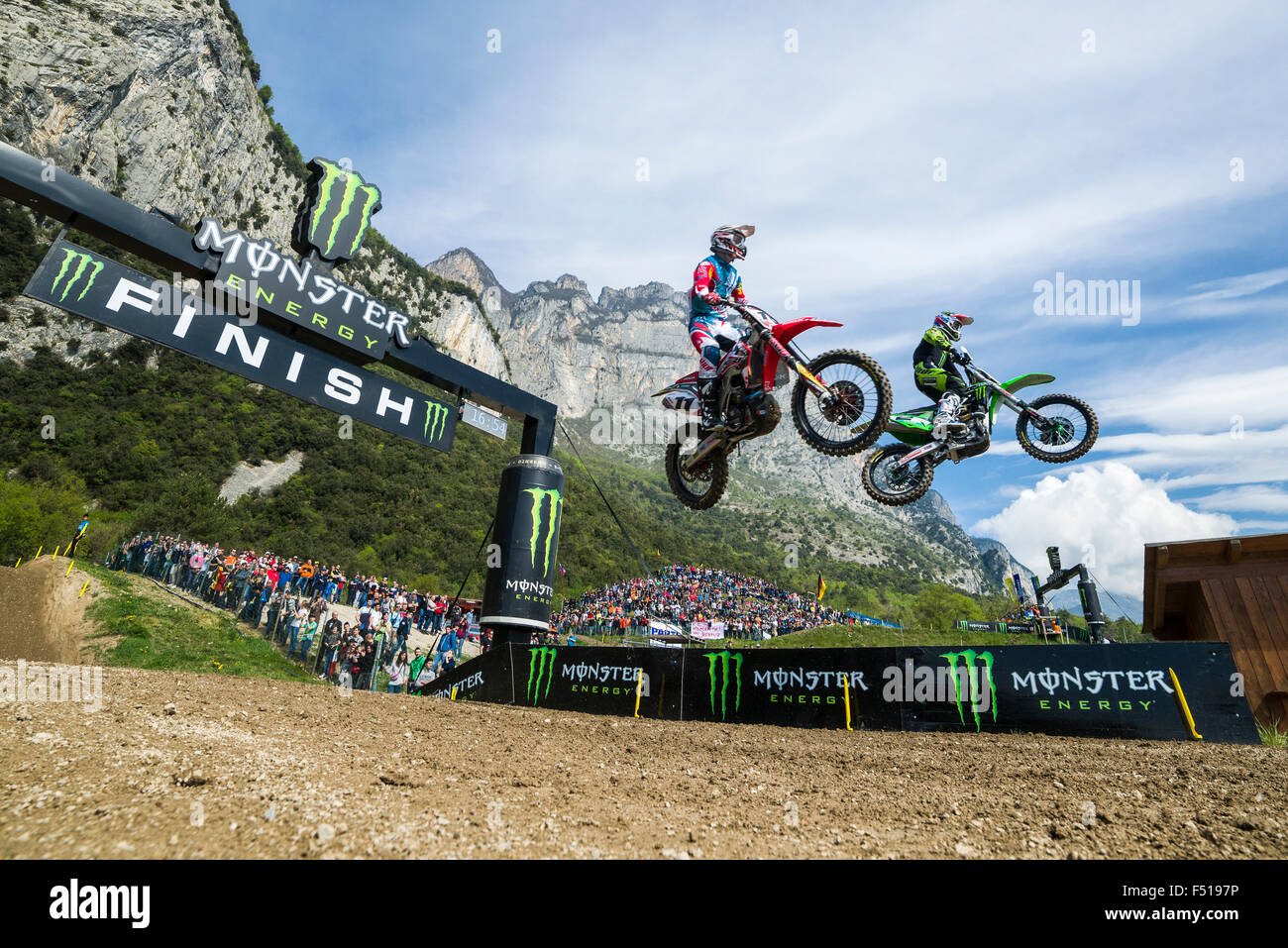 Two motorcyclists on motocross bikes are jumping through the air during ...