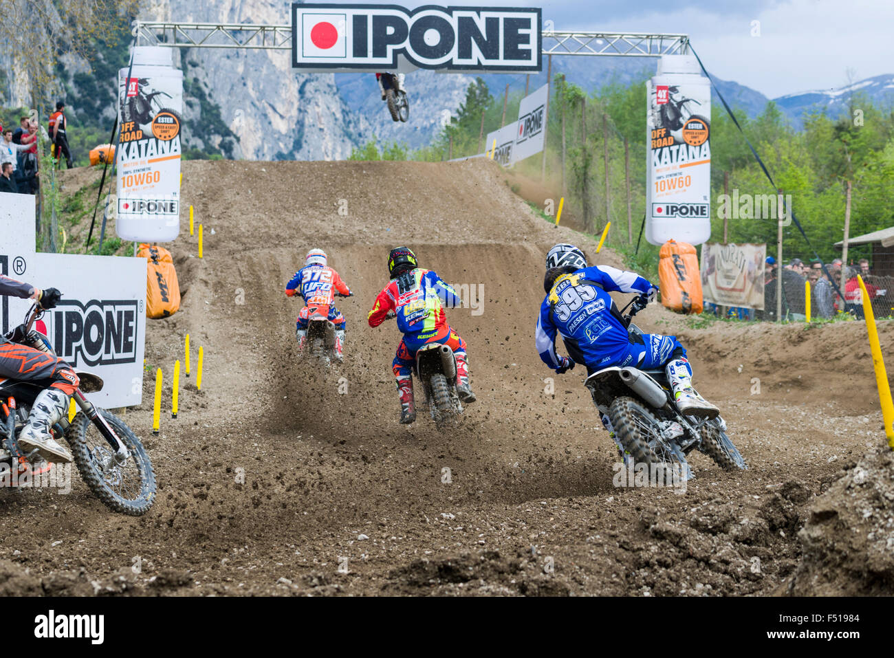 Three motorcyclists on motocross bikes are riding on a dirt track ...