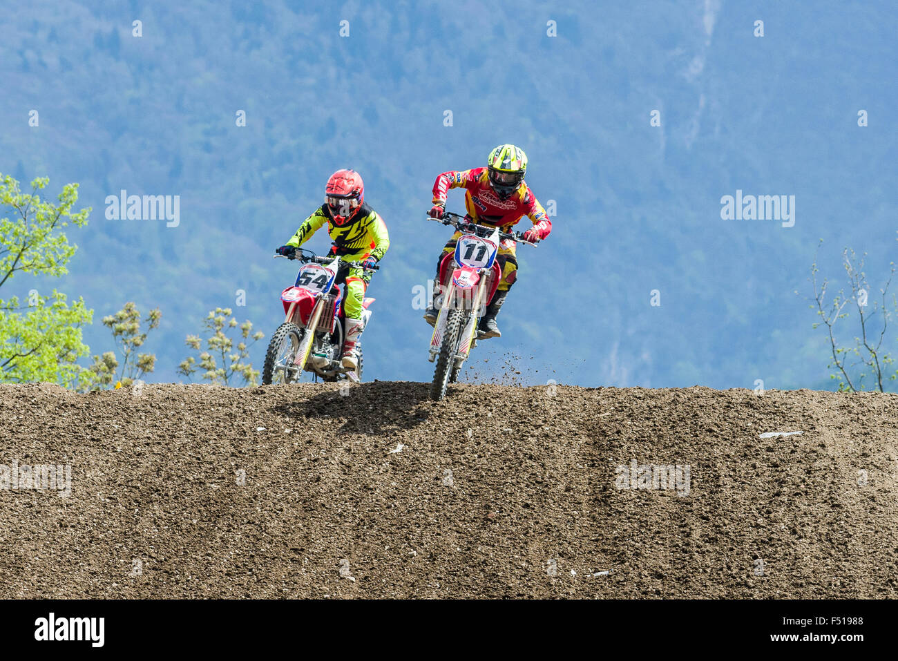 Two motorcyclists on motocross bikes are riding on a dirt track during ...