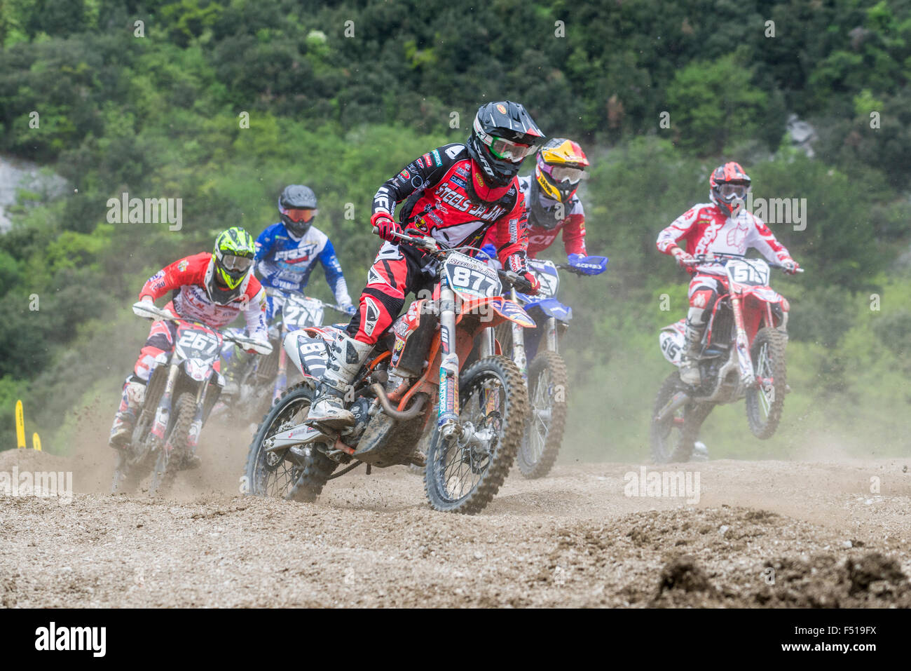 A group of motorcyclists on motocross bikes are riding on a dirt track ...