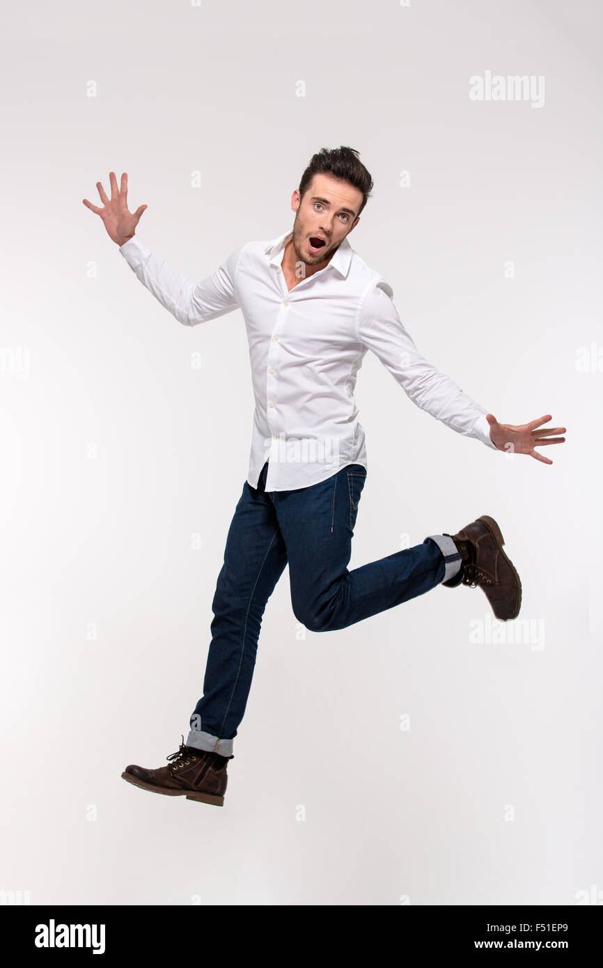 Portrait of a funny casual man jumping isolated on a white background ...