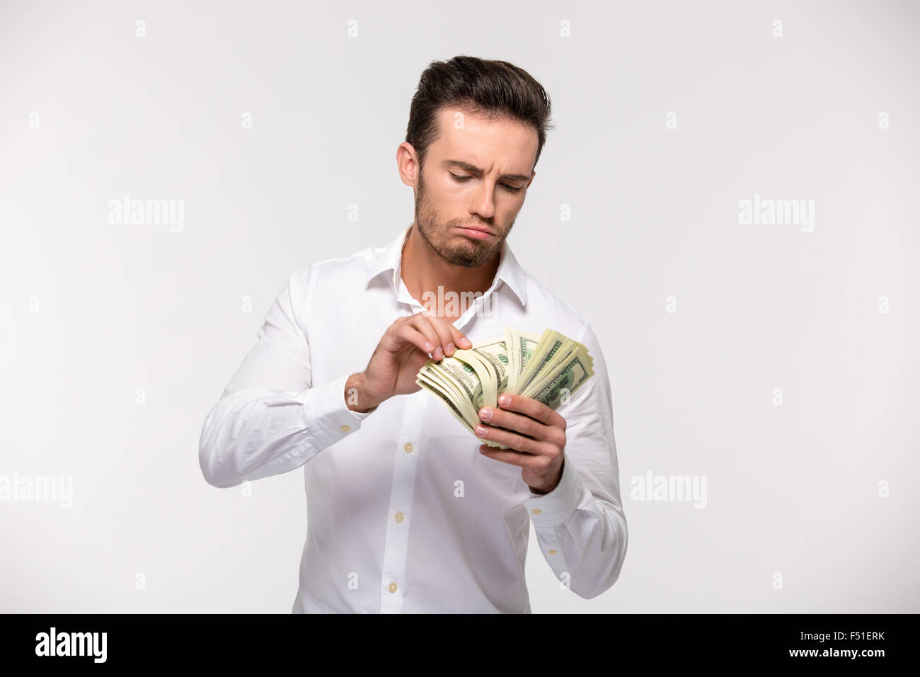 Portrait of a young man counting money isolated on a white background ...