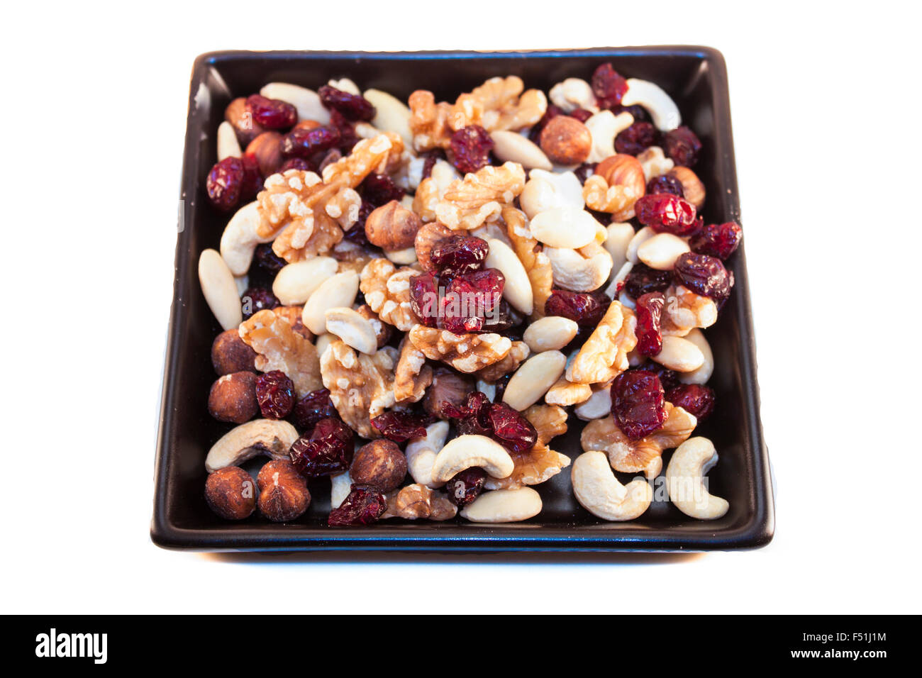 Nut mix with dried cranberries, on a black plate, isolated on white ...