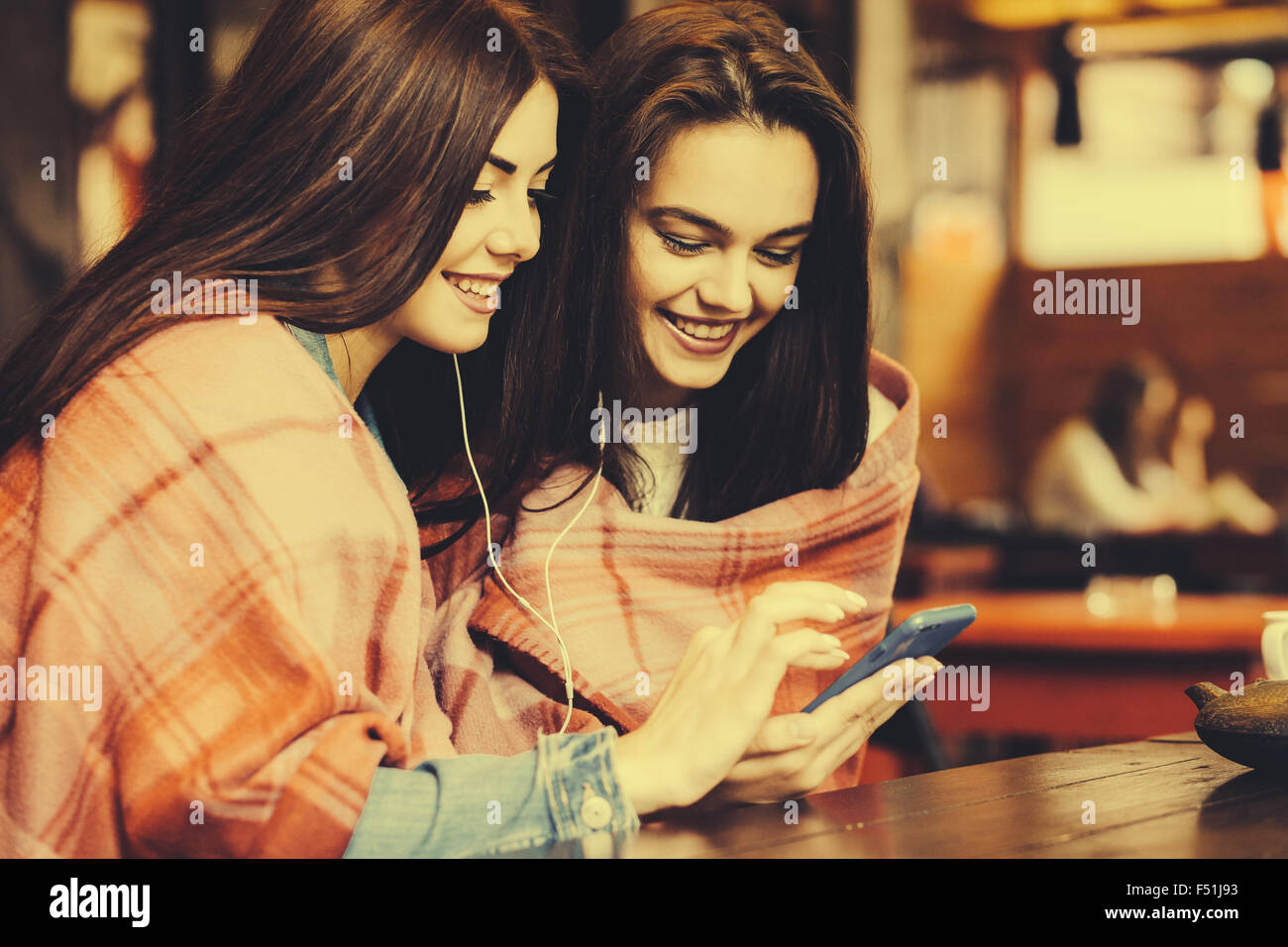 Two girl sitting listening to music Stock Photo - Alamy
