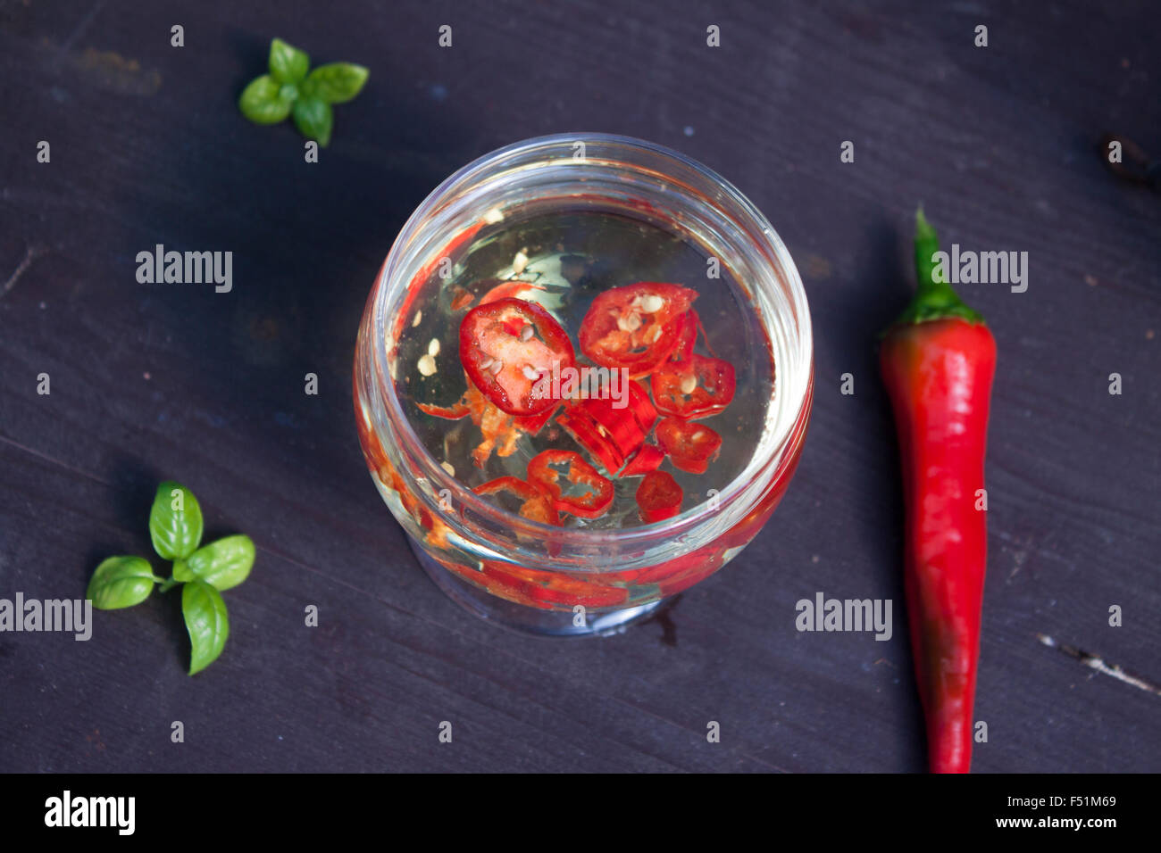 cayenne oil, between capsicum annuum, chili and basil leaves, on wooden ...