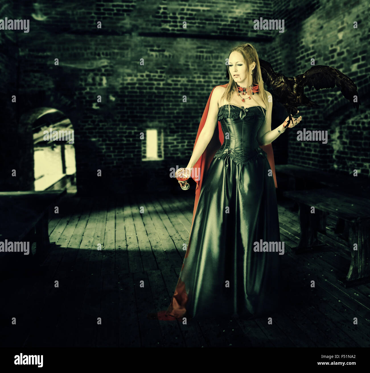 young beautiful female vampire aristocrat with a cup of blood stands in ...