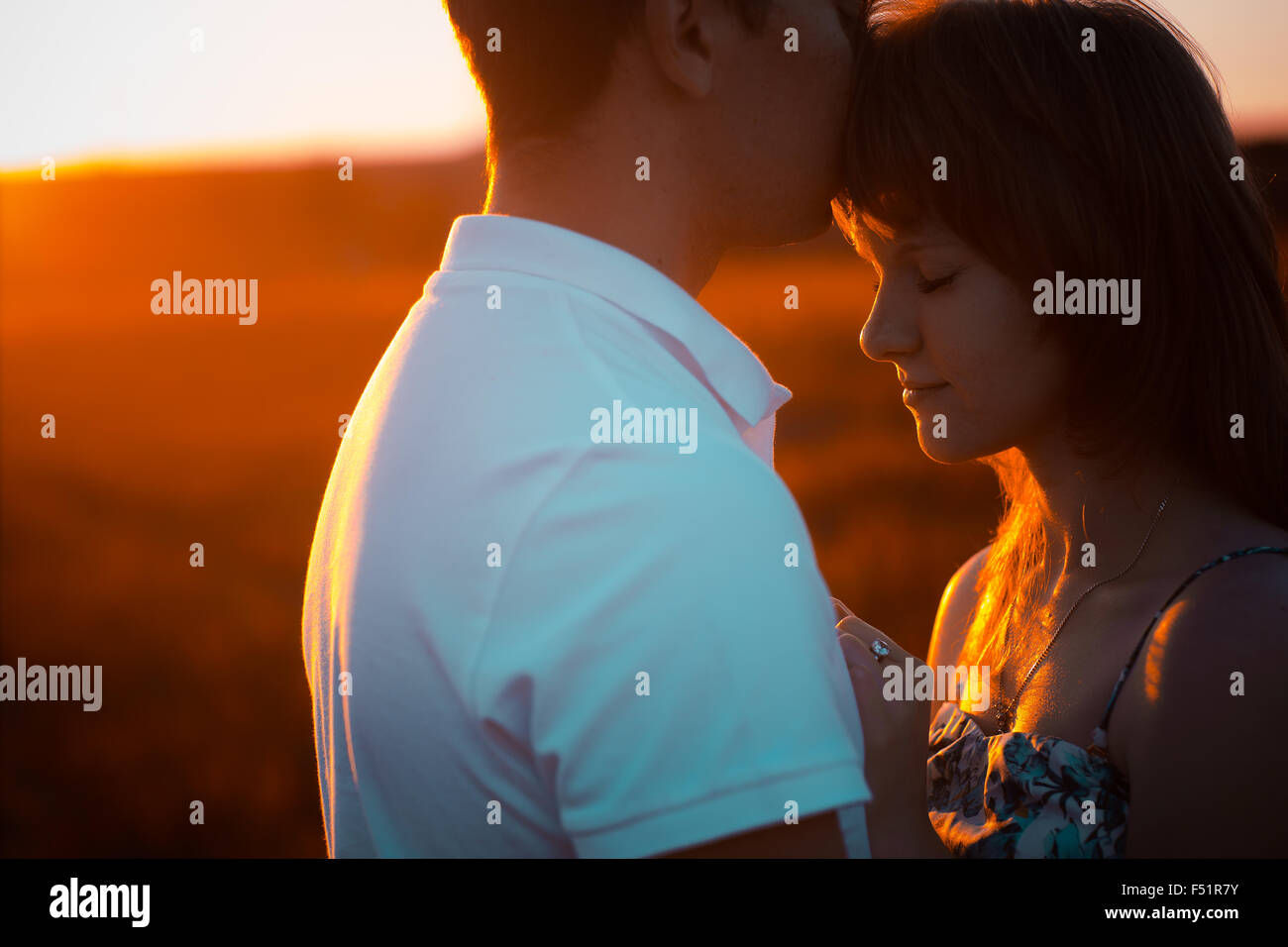 Romantic couple standing and kissing on background summer meadow sunset Stock Photo - Alamy