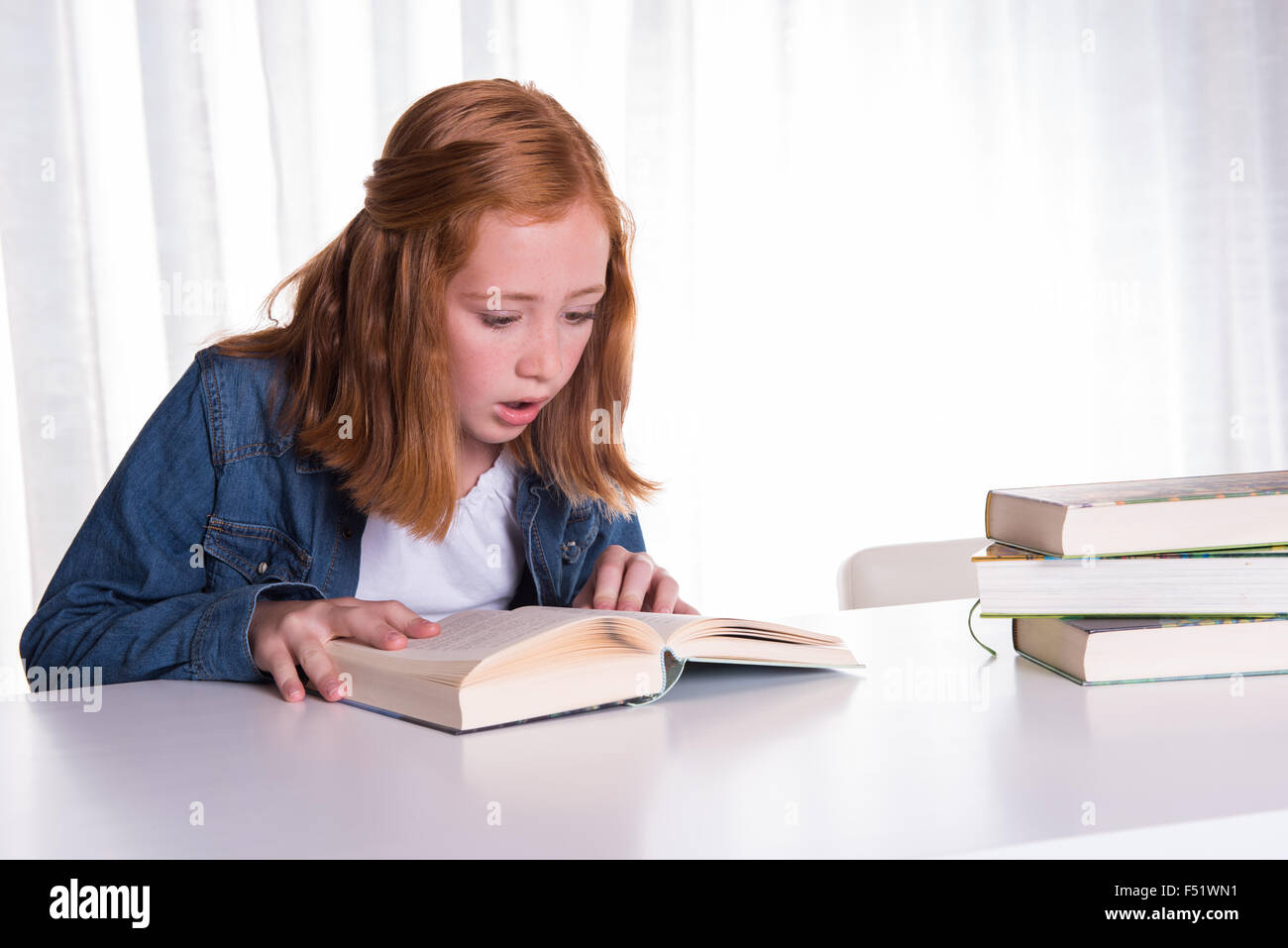 young redhead girl reading in books - she is scared Stock Photo - Alamy