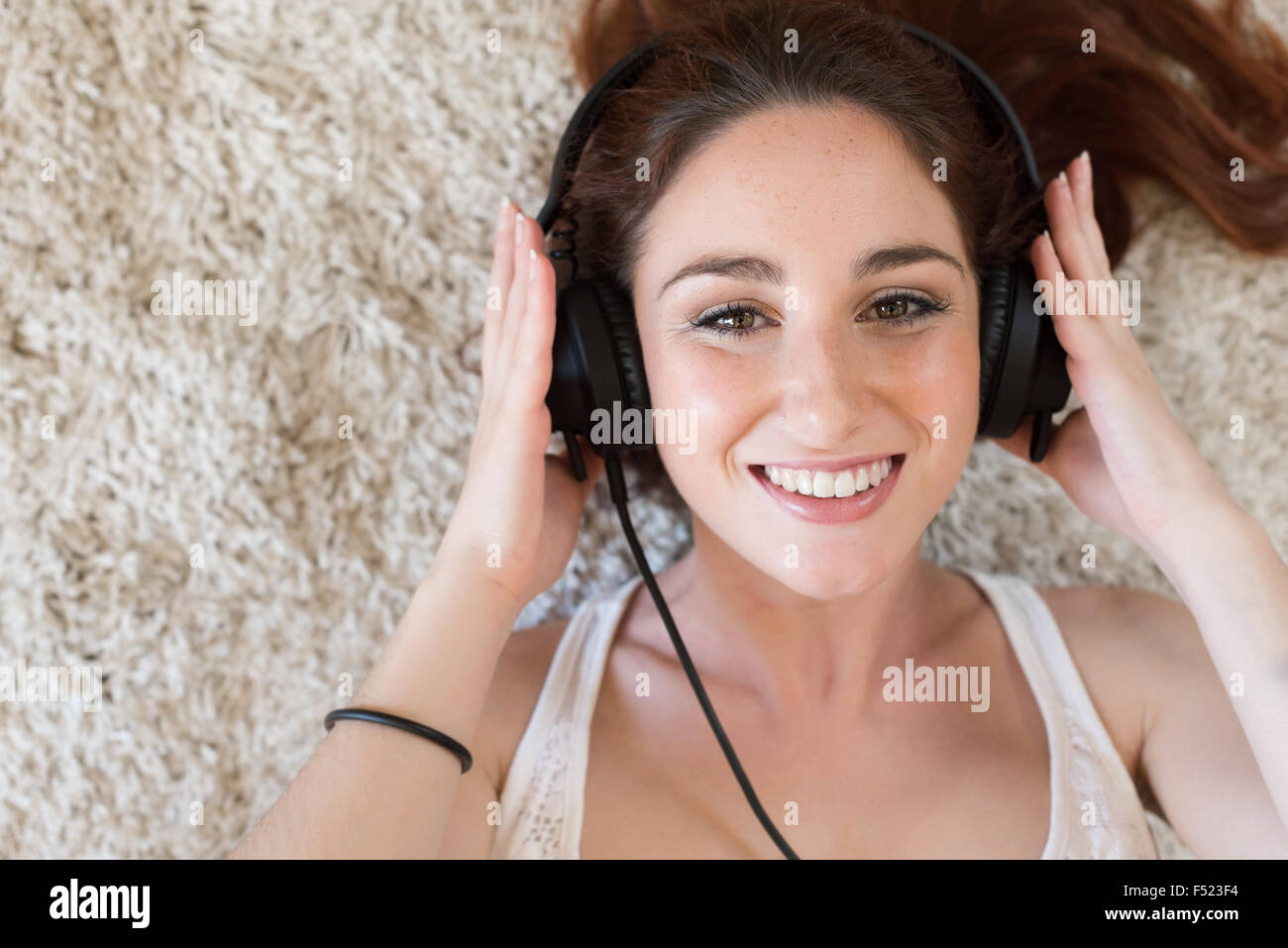 Woman laying on carpet with headphones Stock Photo - Alamy