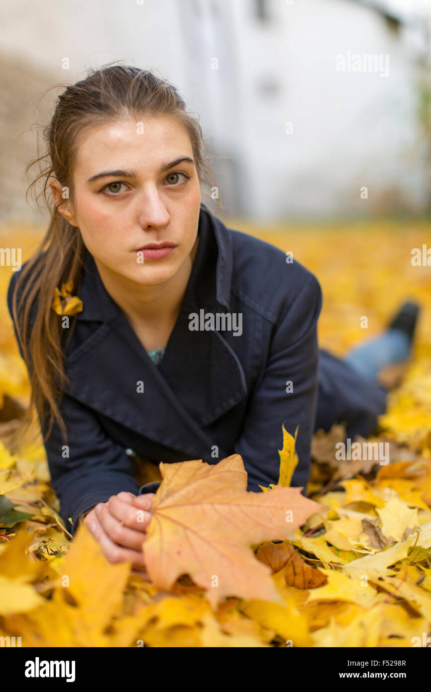 Portrait of young girl lying in fallen leaves Stock Photo - Alamy
