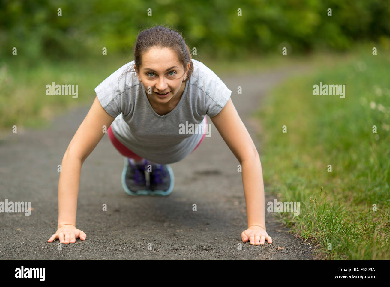 Young girl doing push-ups from the ground, a warm up before your jog ...