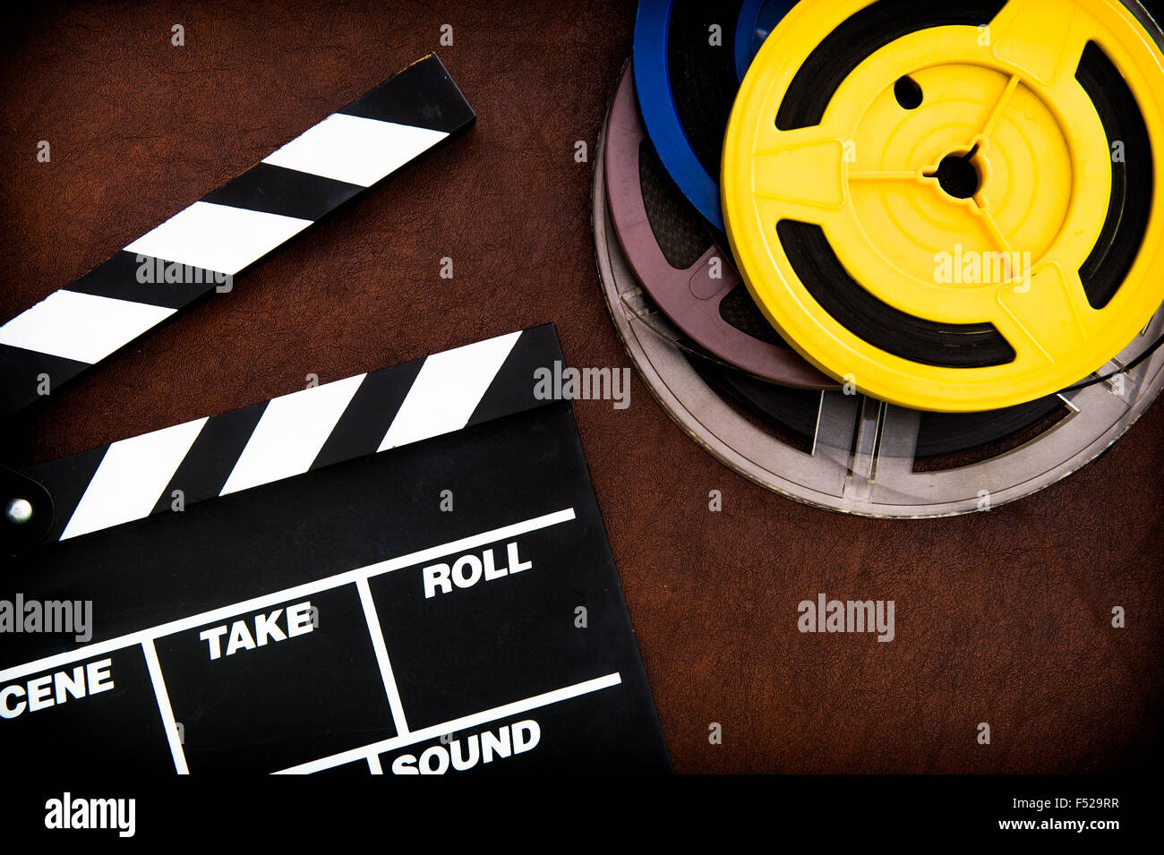 Movie clapper board detail and colored film reels on brown table Stock ...