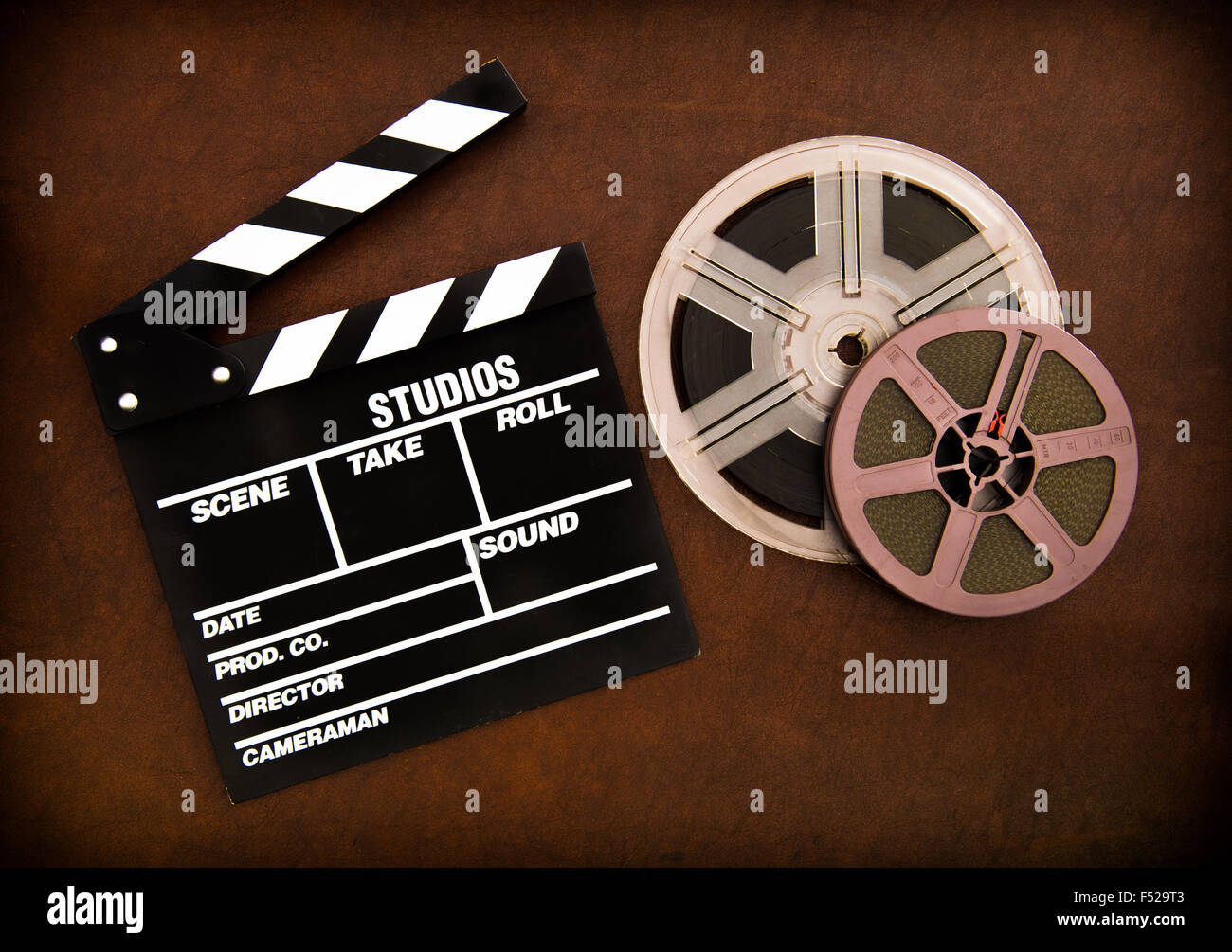 Movie clapper board and colored film reels detail on brown table Stock ...