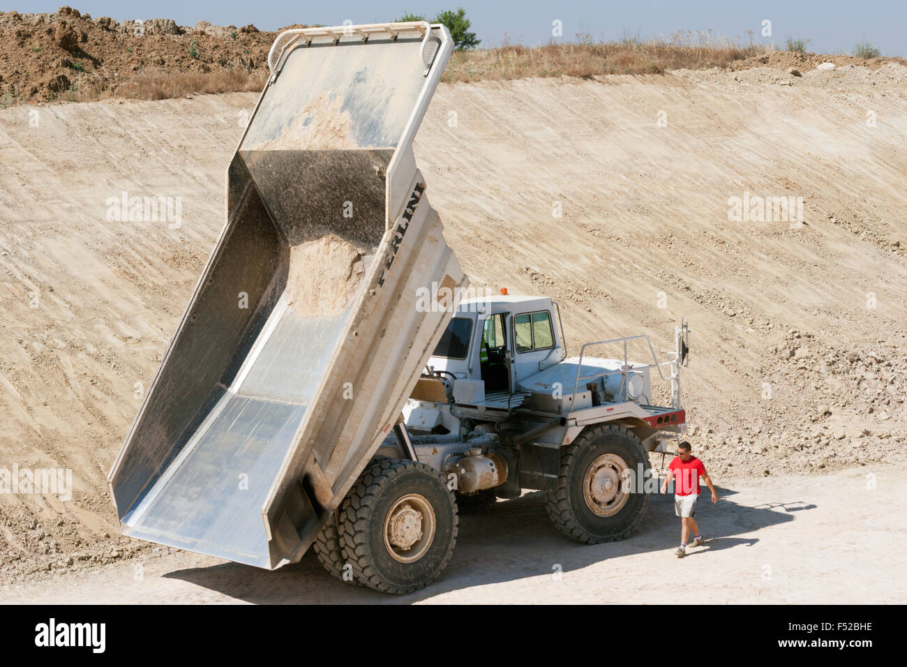 Man standing next to mining truck at work site Stock Photo - Alamy
