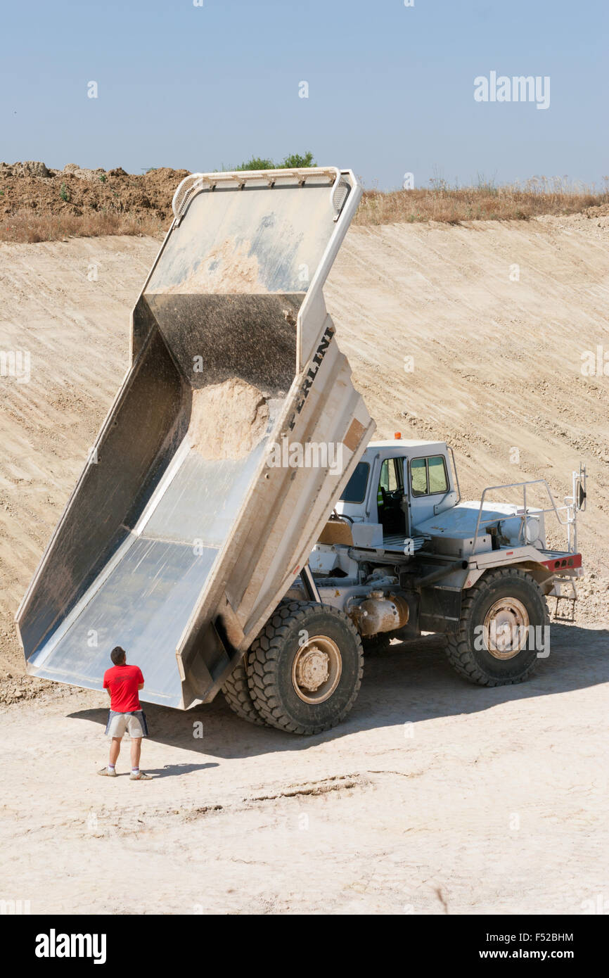 Man standing next to mining truck at work site Stock Photo - Alamy