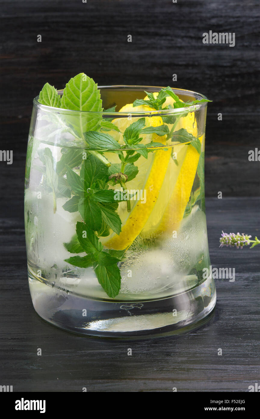 Homemade mojito cocktail in a curved glass on against dark background ...