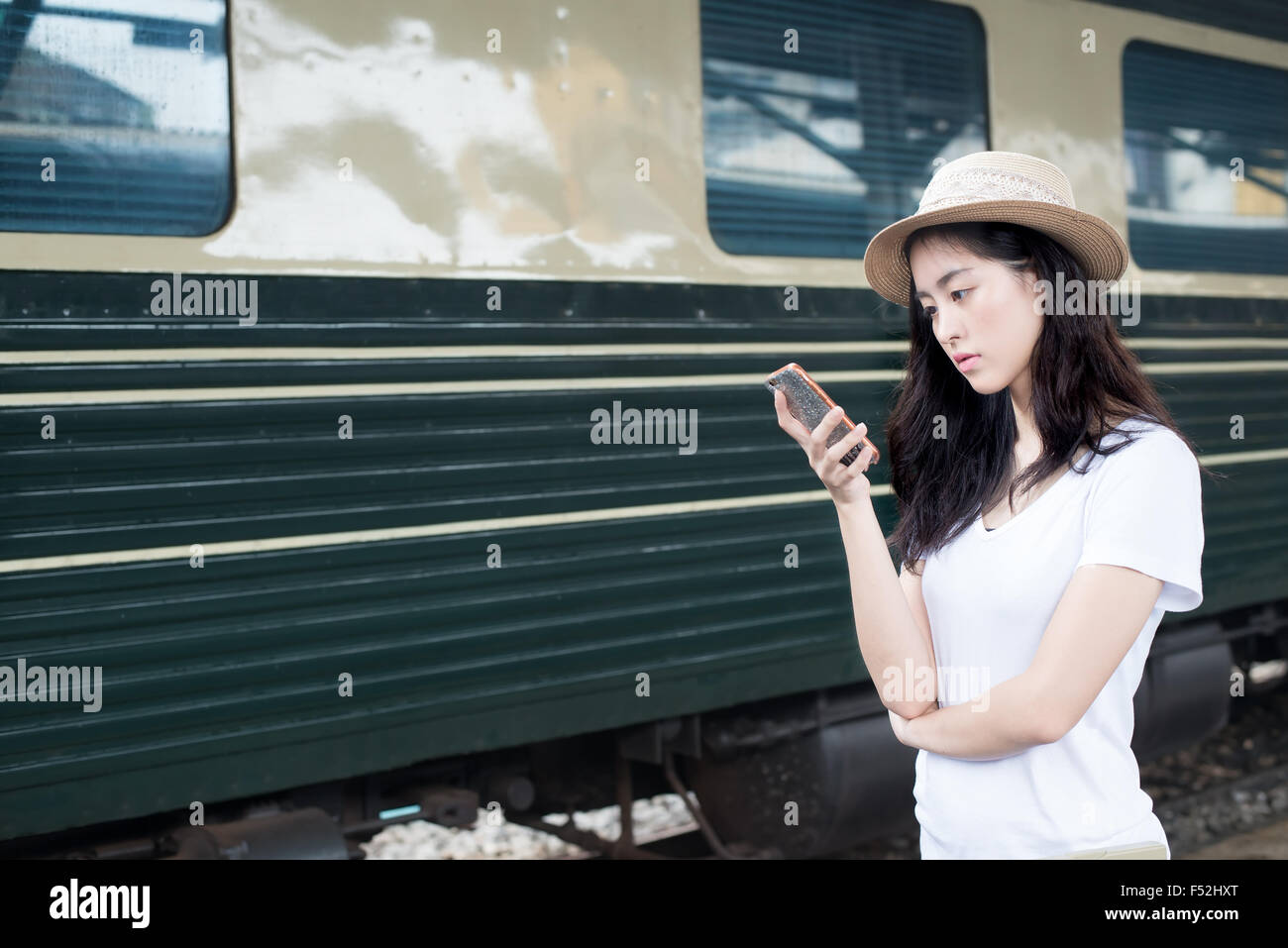 Asian woman texting on smartphone at train station with railway in ...