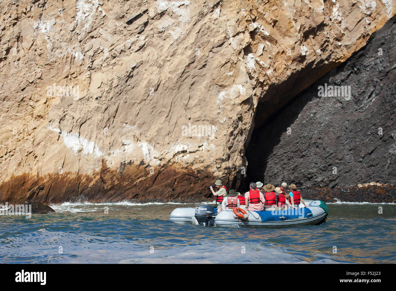 Tourists in panga viewing geological contact between tuff (compacted ...