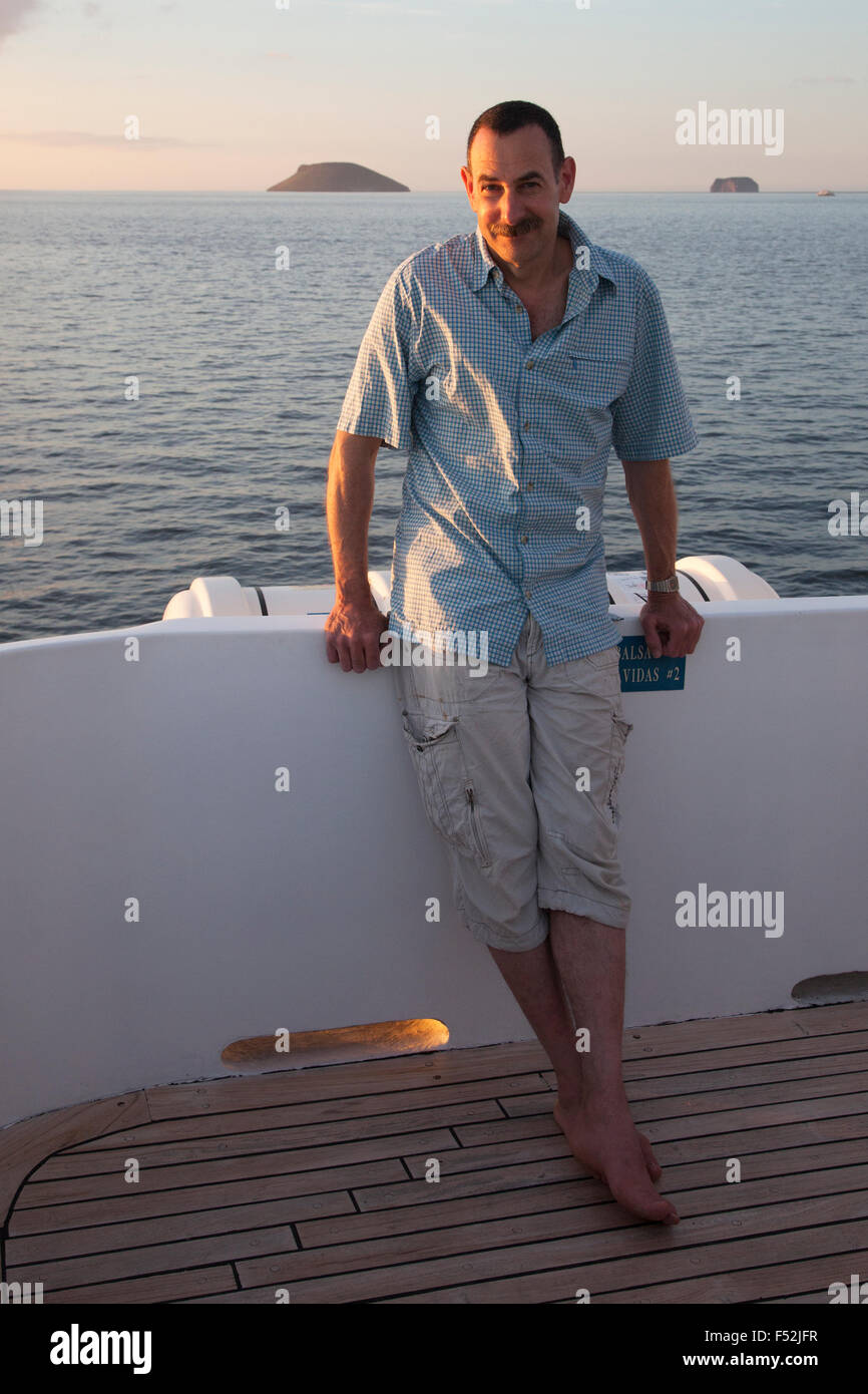 Barefoot tourist relaxing on deck in cruise boat, Galapagos Islands at ...