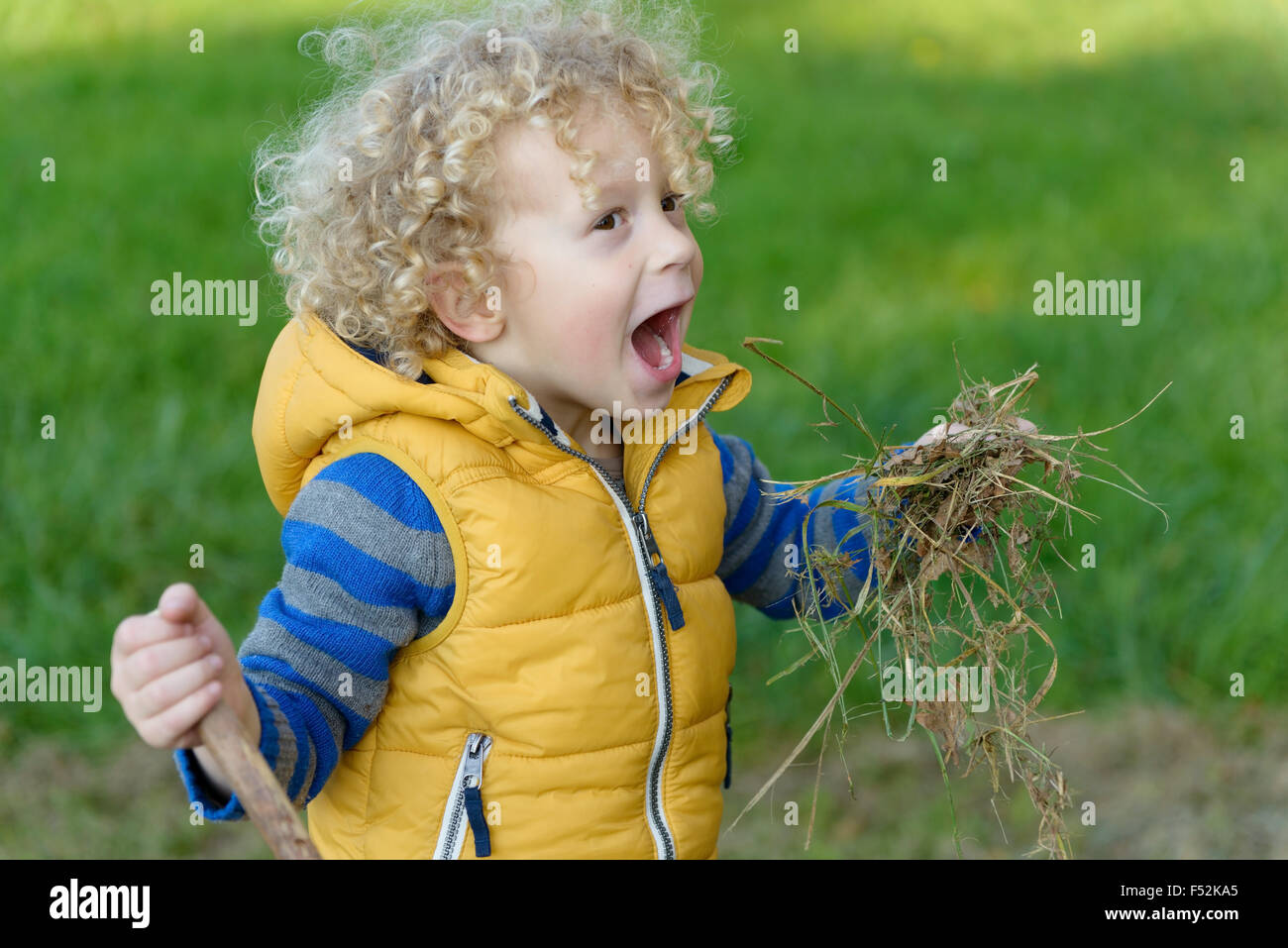 a little blond boy playing with a stick, outside Stock Photo - Alamy