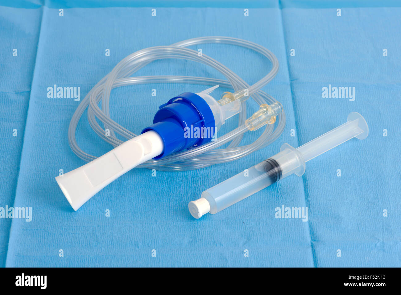Inhalation therapy chamber and sterile saline syringe on blue sterile ...