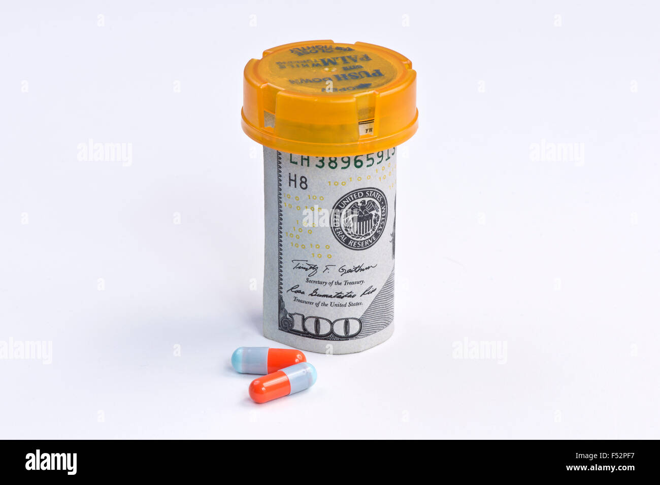 One hundred dollar bill with prescription bottle cap and capsules Stock ...