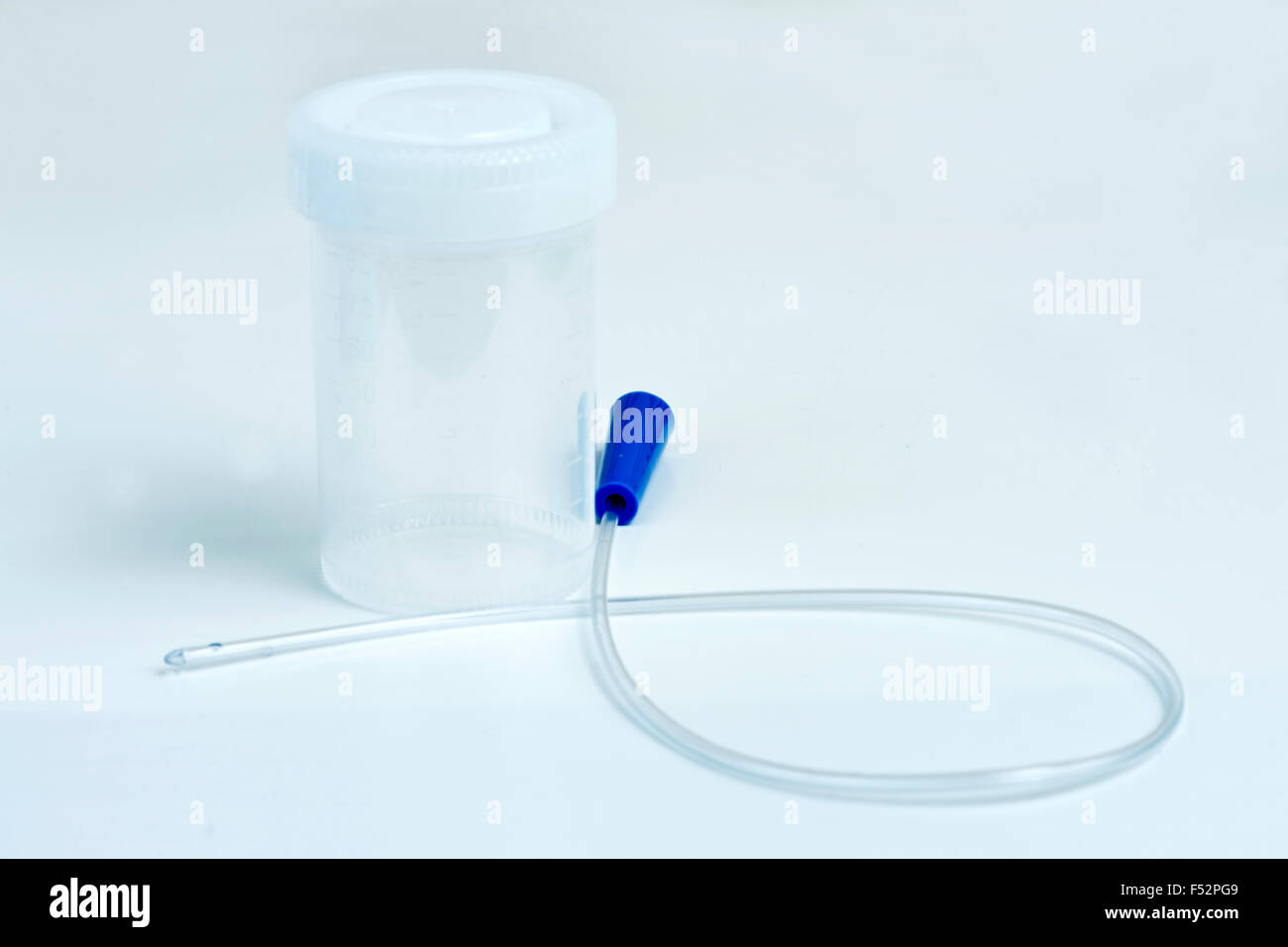 Urinary catheter and specimen collection cup on light background Stock ...
