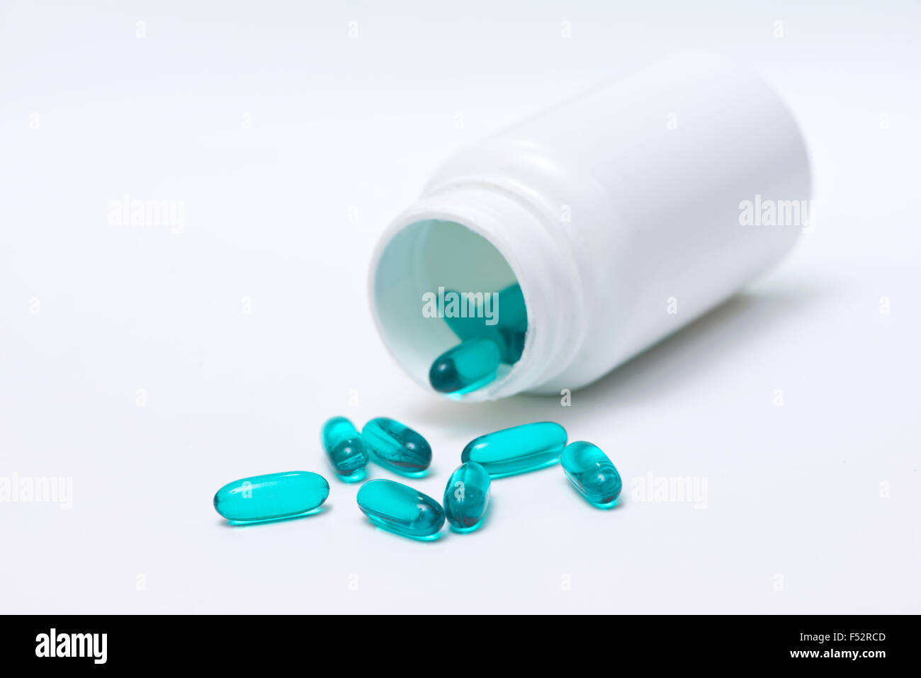 Blue gelatin capsules spill from white bottle Stock Photo - Alamy