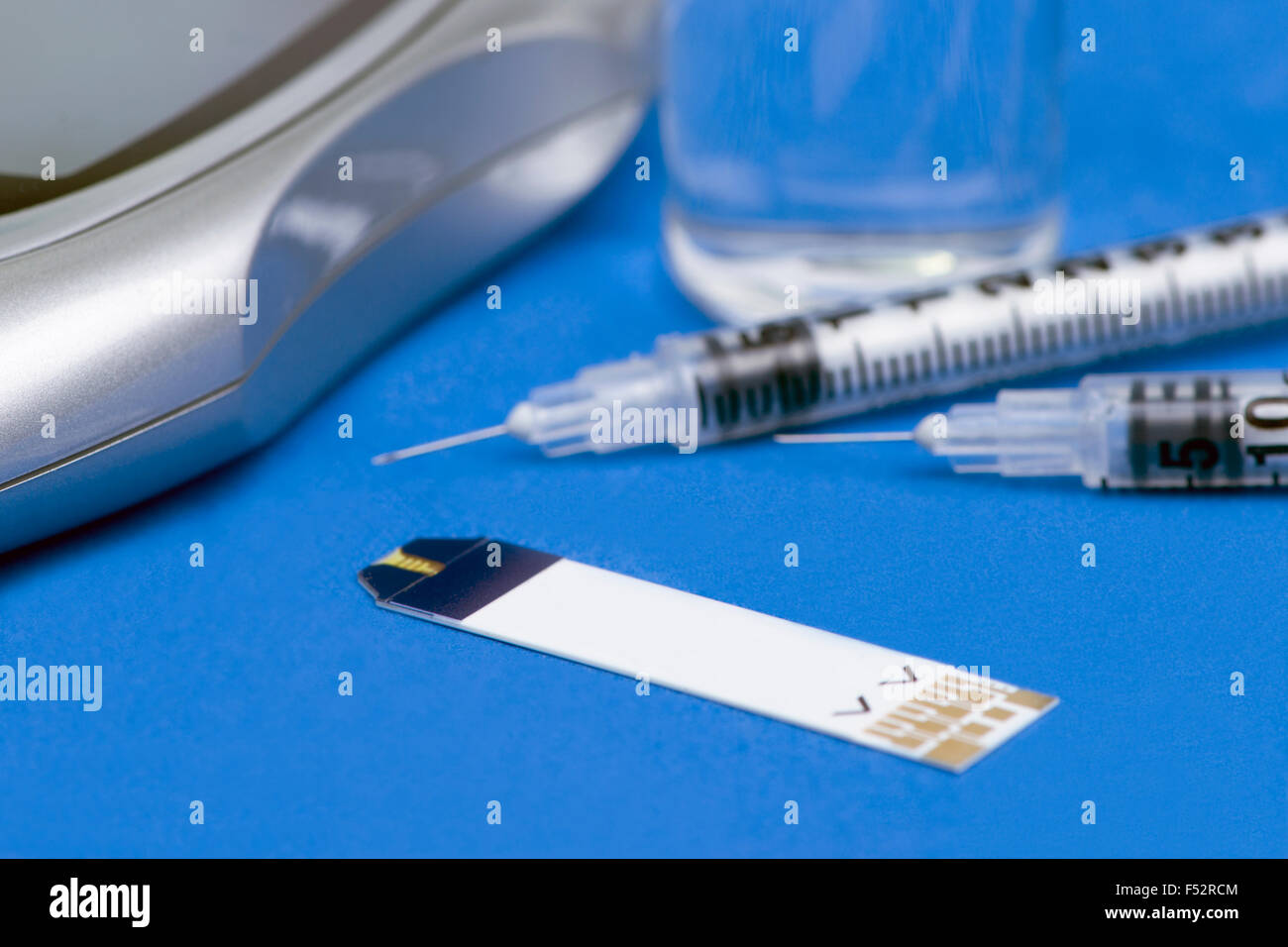 Close-up view of diabetic test strip with glucometer, insulin vial and ...