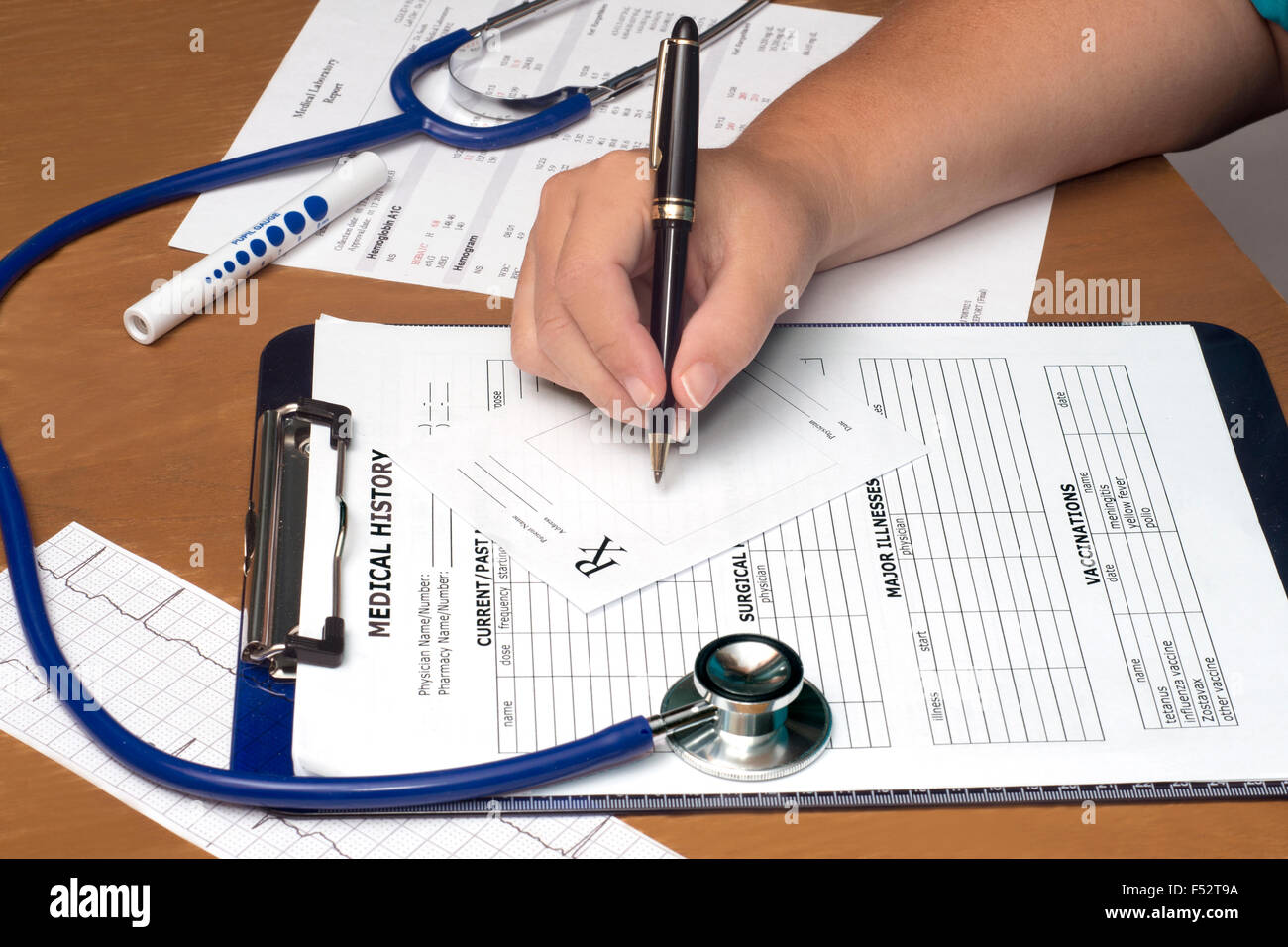 Doctor writing prescription on desk with patient chart Stock Photo - Alamy