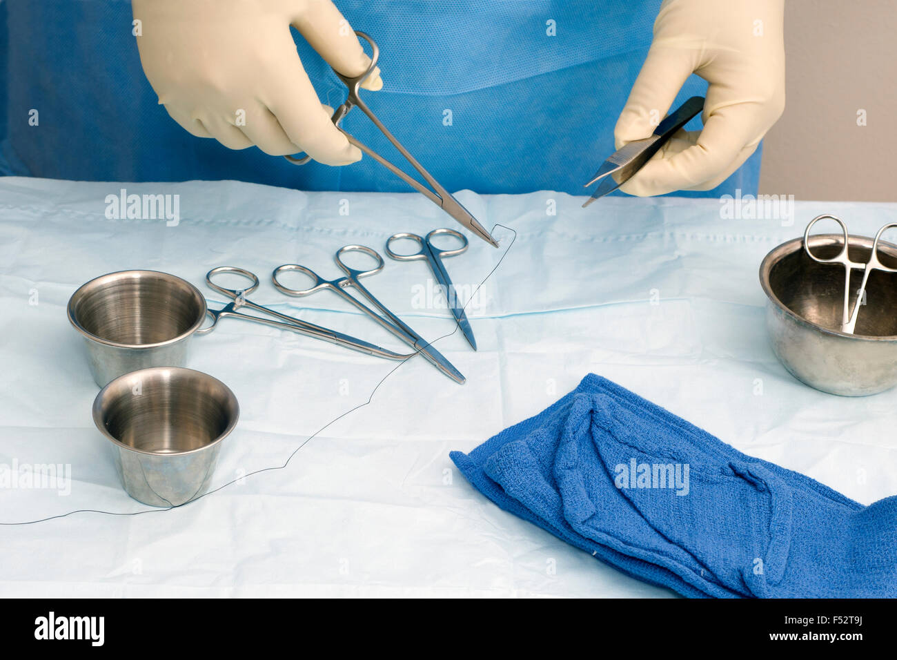 Surgeon picks up forceps and suture from sterile table Stock Photo - Alamy
