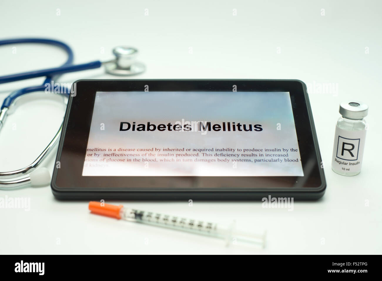 Tablet computer showing diabetes fact sheet, stethoscope, insulin vial ...