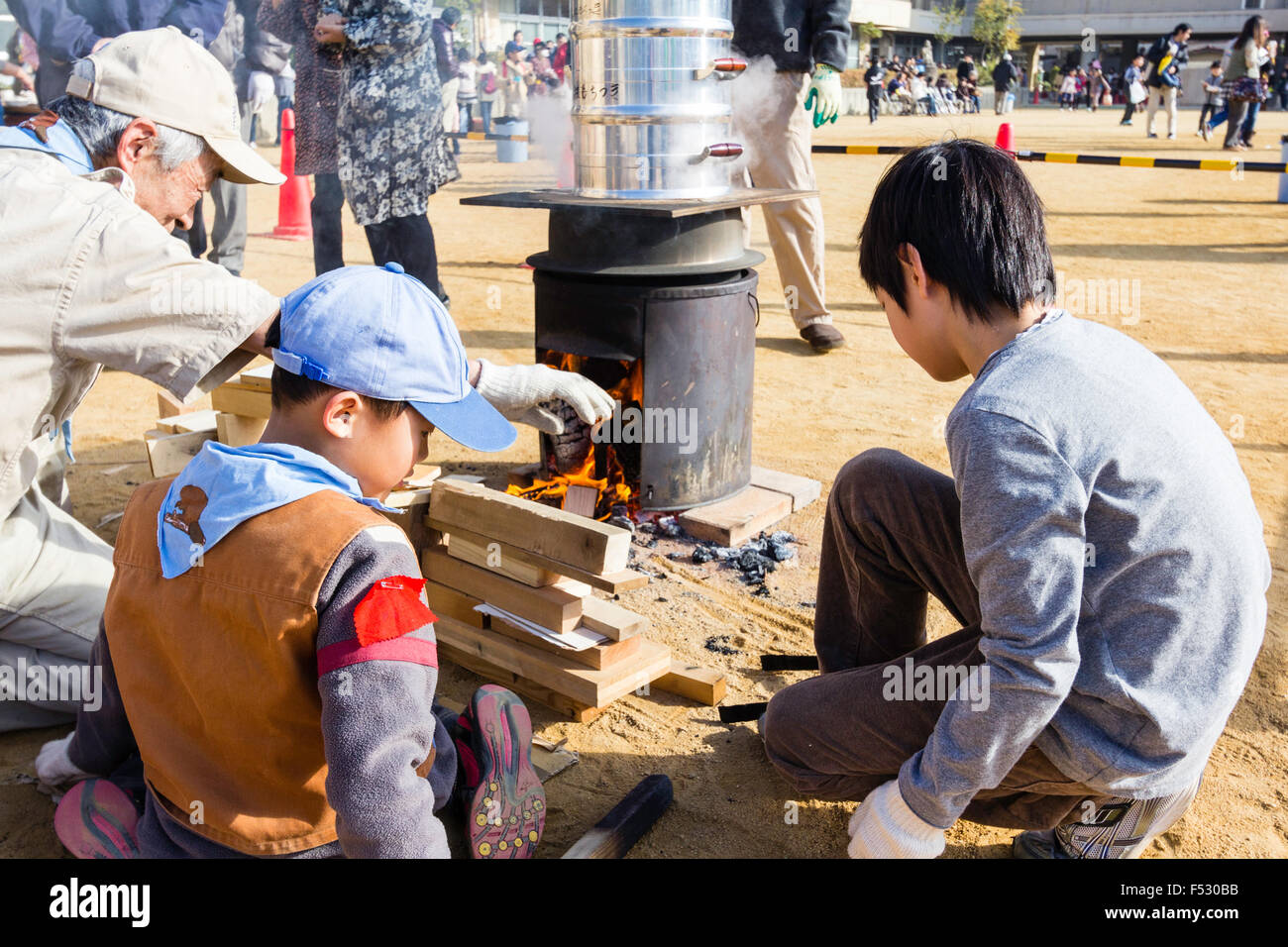 Japan. Omochi, rice bashing festival. Boy scouts firing stove with wood ...