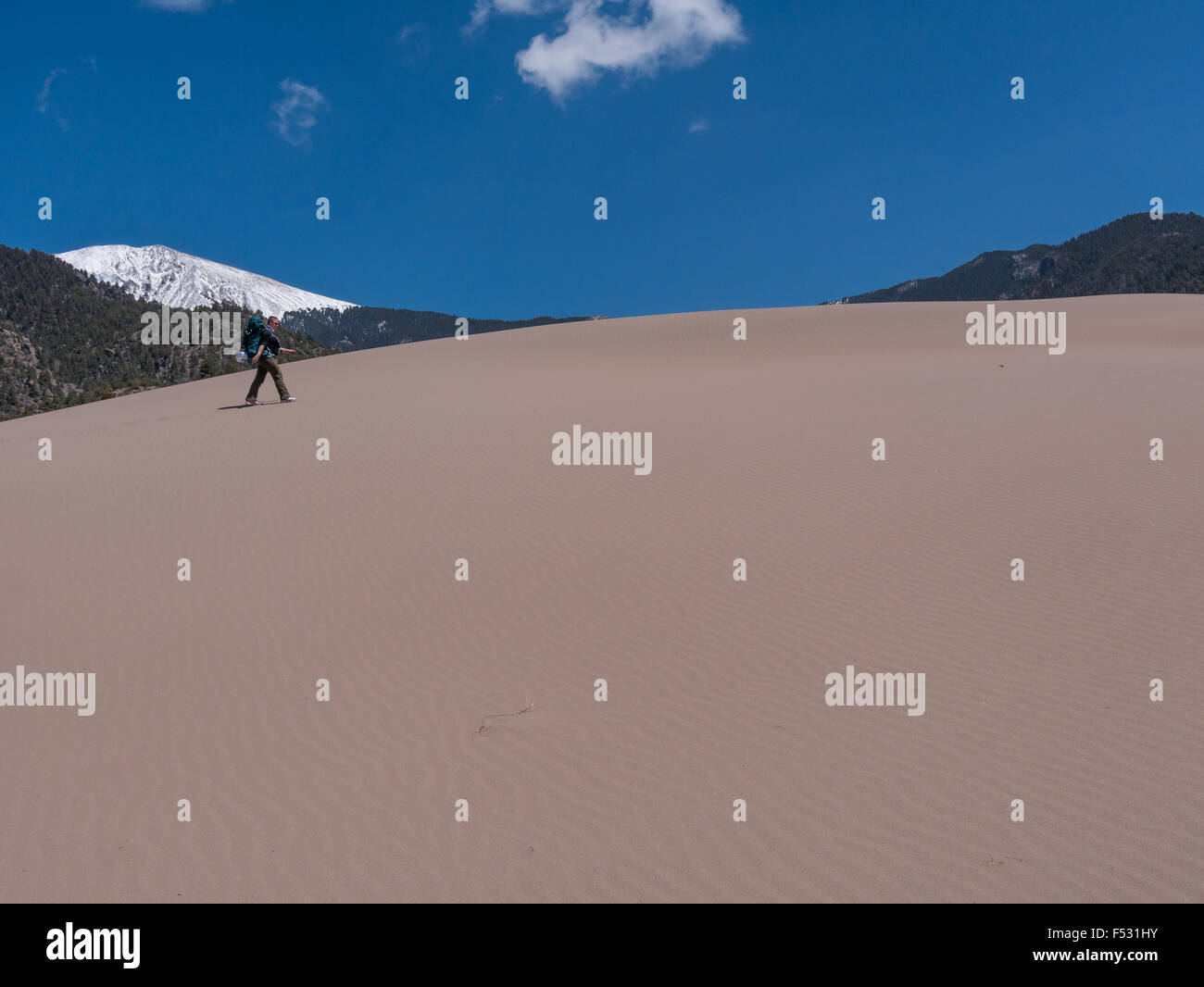 Backpacker walking across dune at Great Sand Dunes National Park in ...