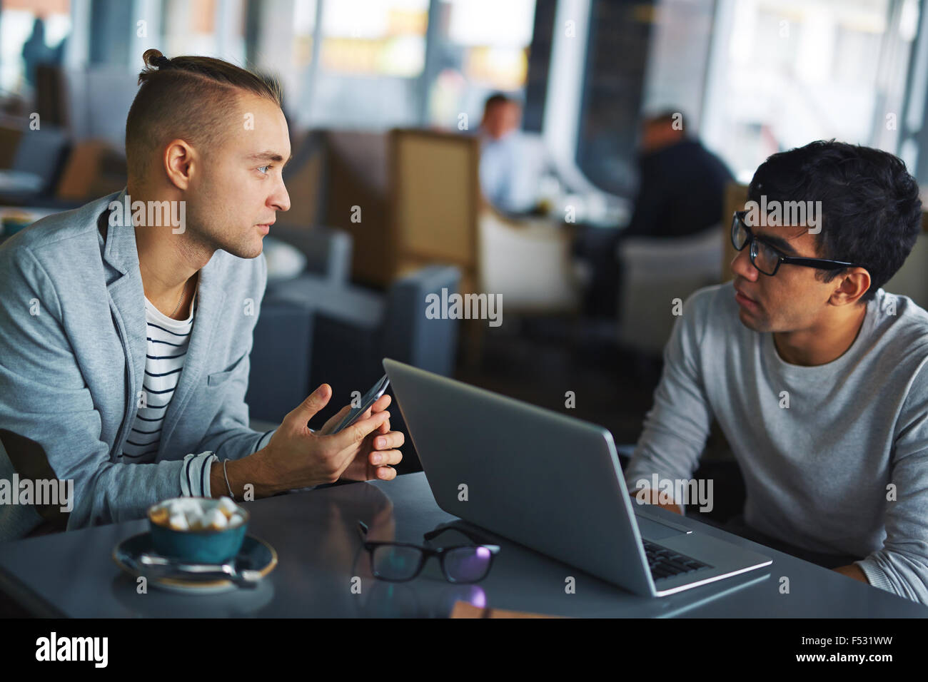 Two modern guys having conversation Stock Photo - Alamy