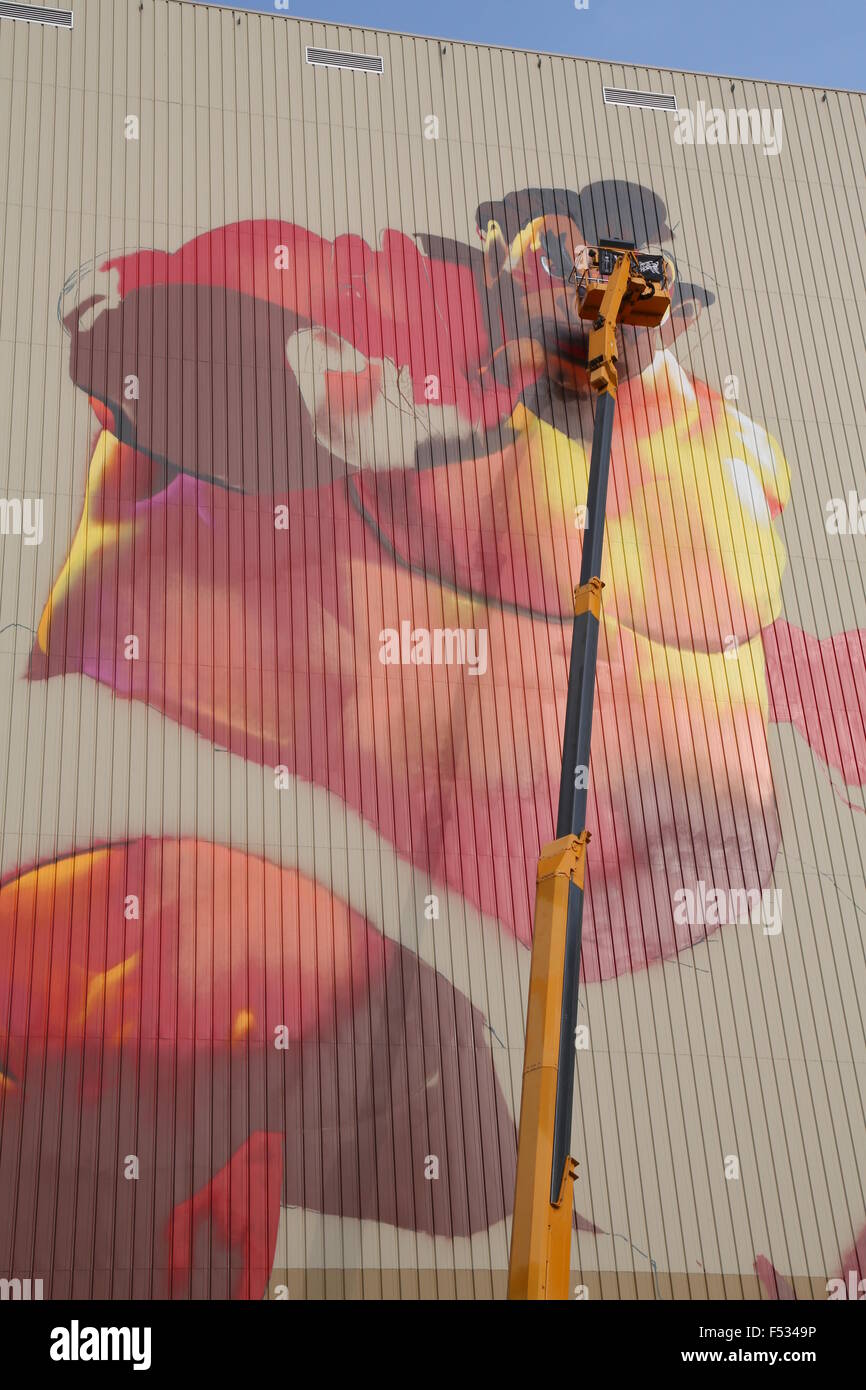 An artist paints a giant wall mural depicting a sumo wrestler on ...