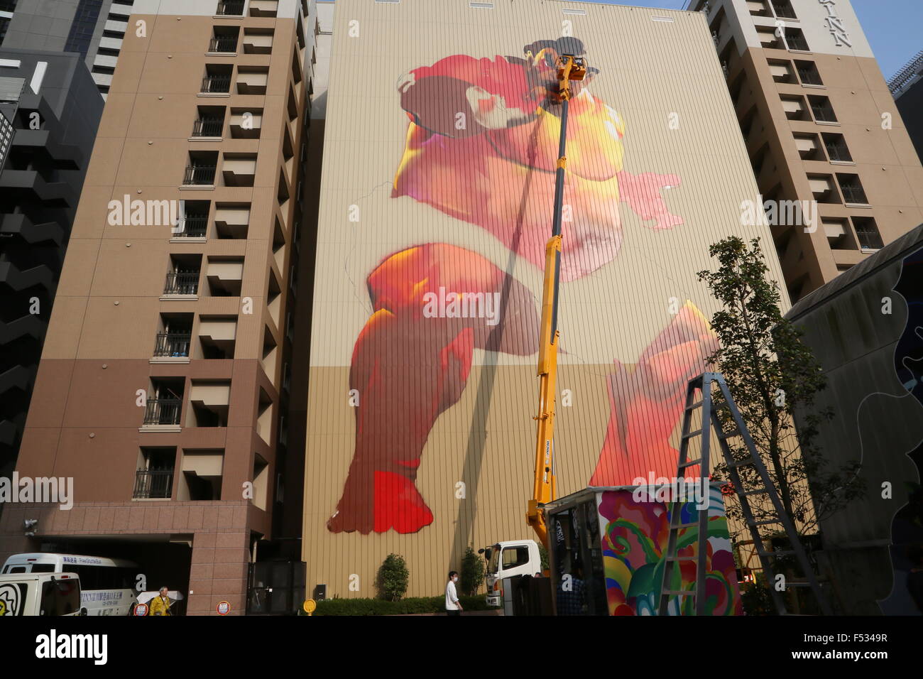 An artist paints a giant wall mural depicting a sumo wrestler on ...