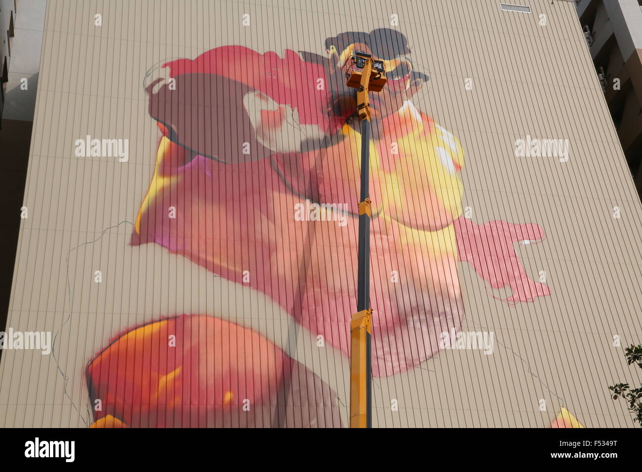 An artist paints a giant wall mural depicting a sumo wrestler on ...