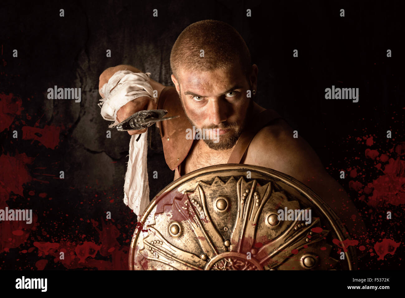 Gladiator posing with shield and sword in a dark background with blood ...