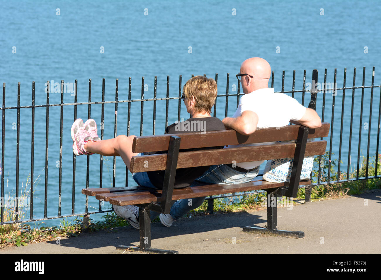 Tourists sat on bench looking at view of Torbay from Babbacombe Downs ...