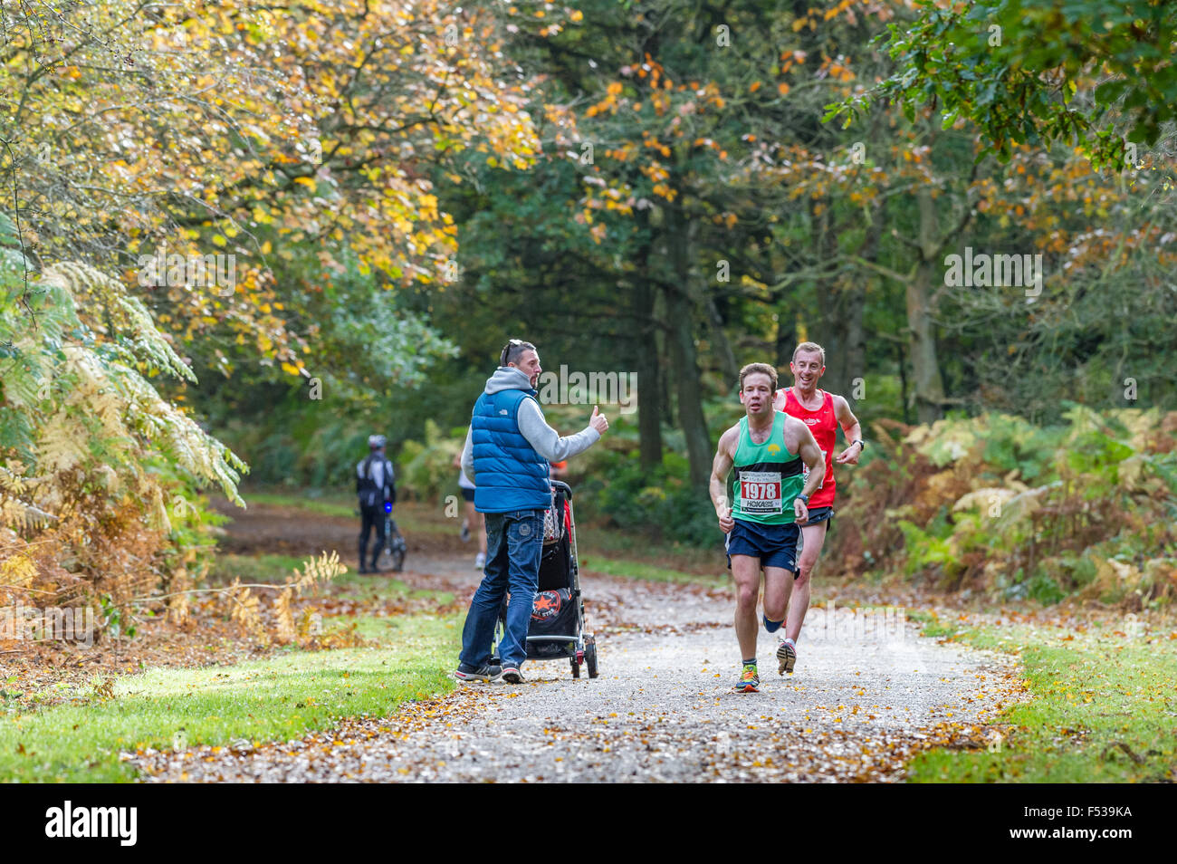 Man gives the thumbs-up to runners running in a half marathon through a ...